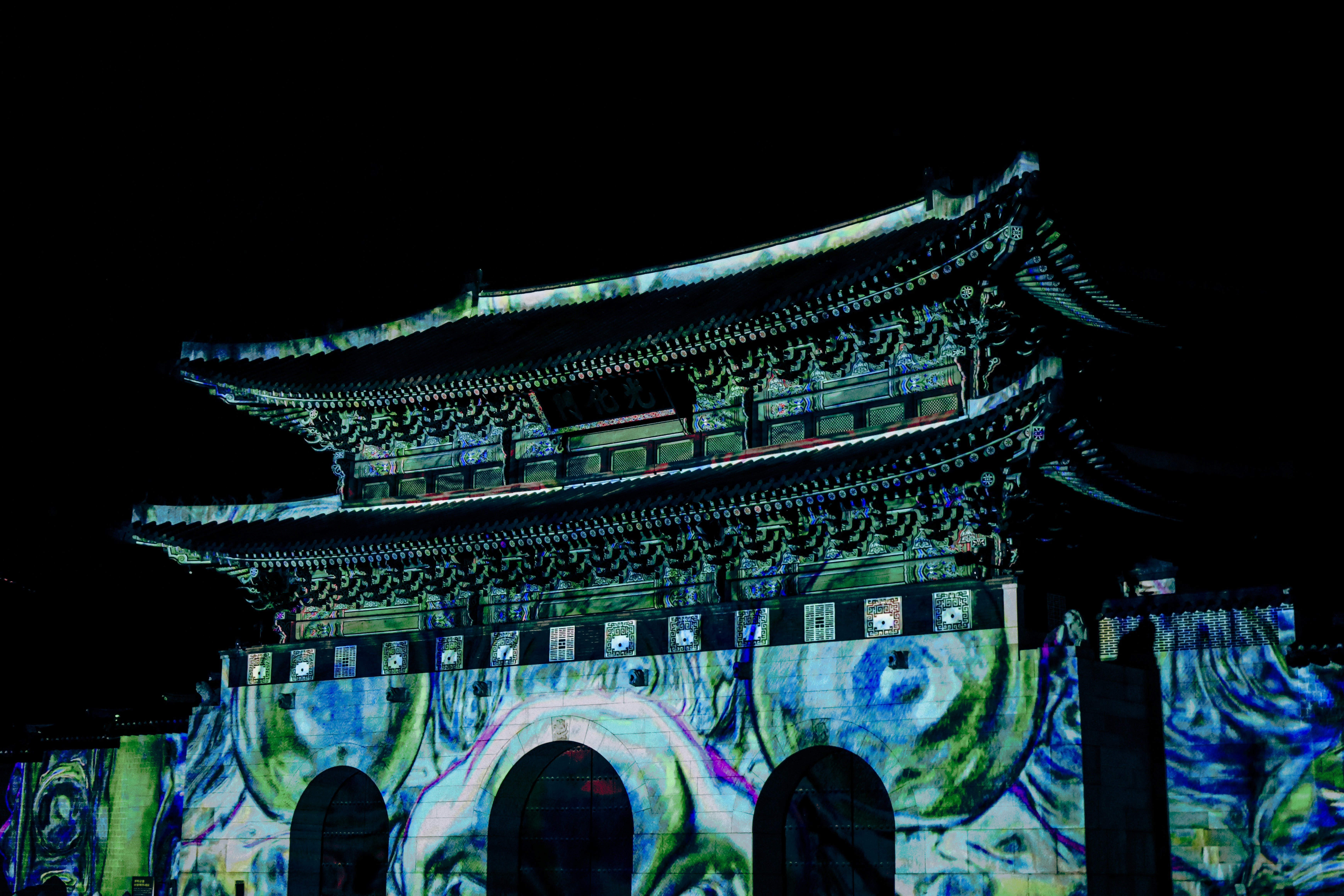 Projection-Draped Gate: Neon Swirls Enliven a Historic Archway