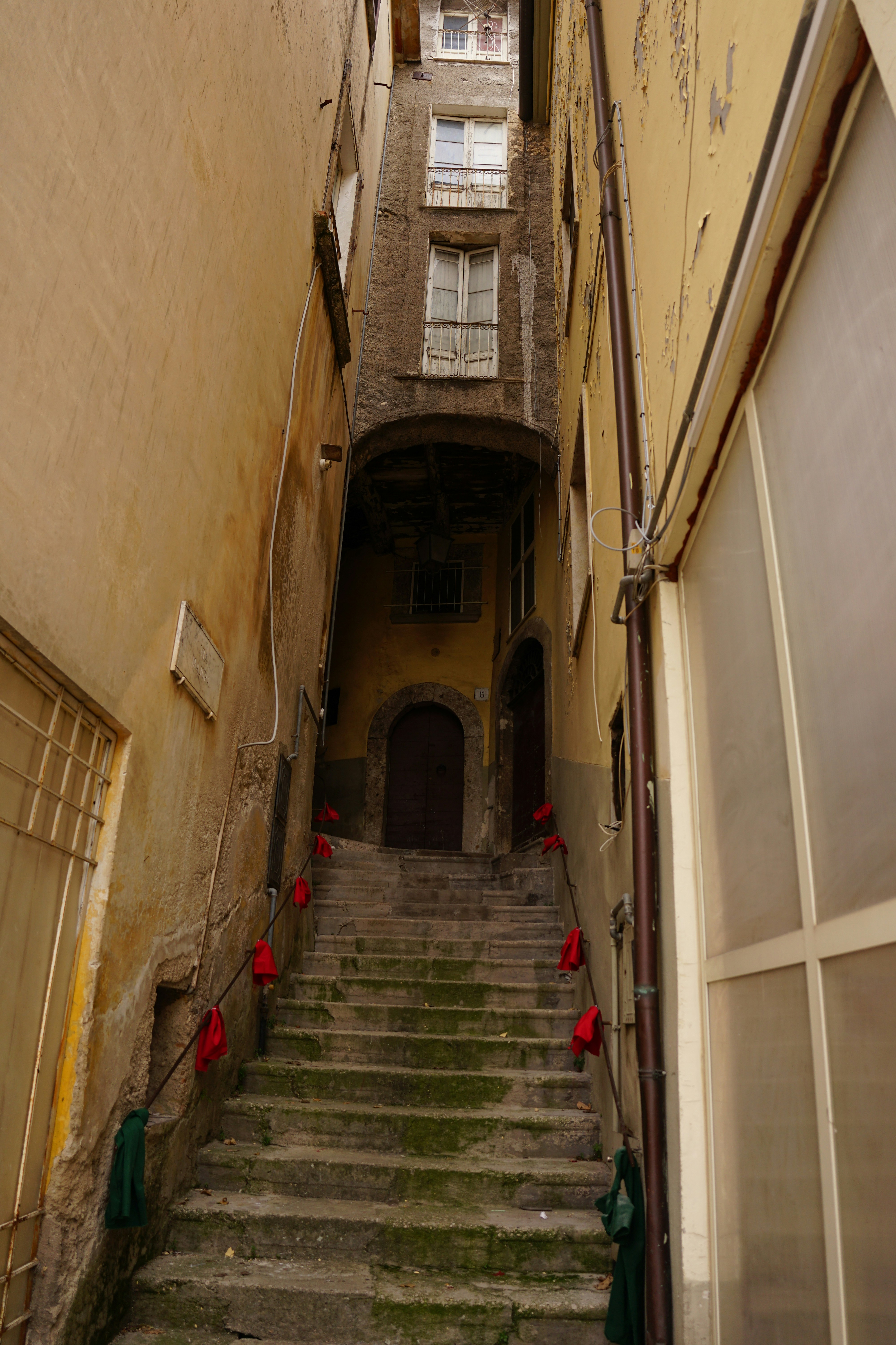 Staircase to a shadowed archway between ochre facades