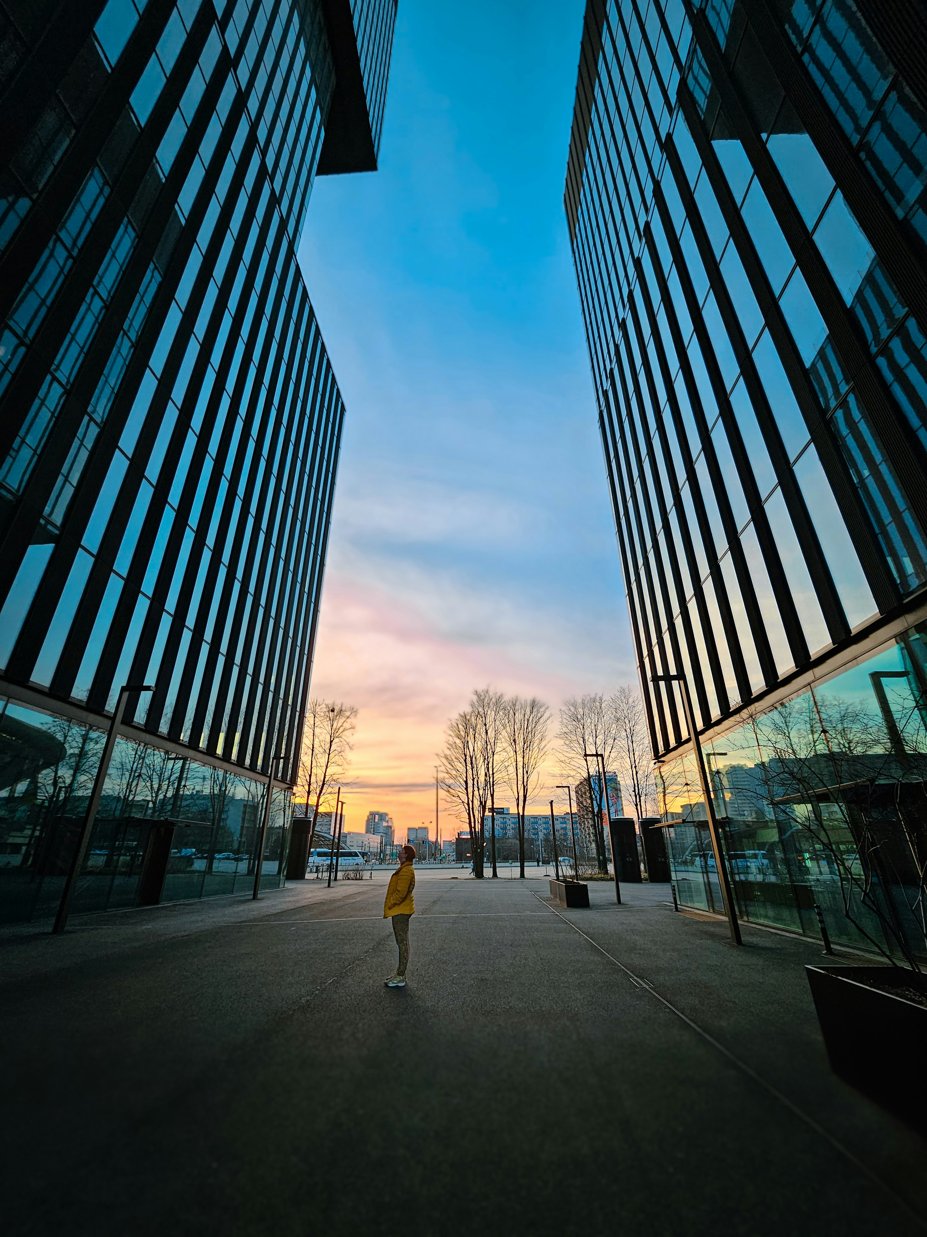 A person standing in the middle of a walkway between two tall buildings ...