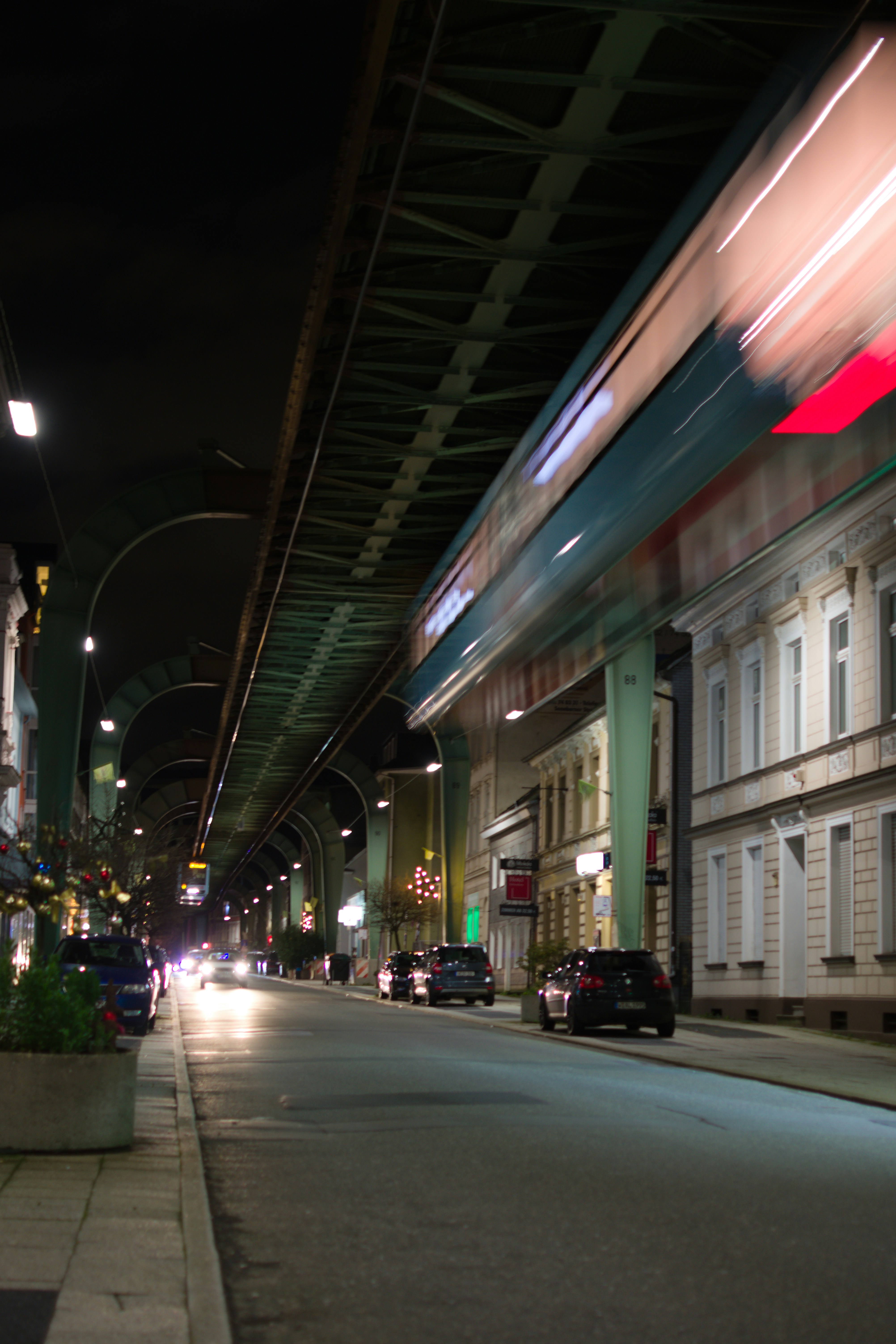 Night Rush Under a Green Viaduct: Blurred Subway Slicing Past a Quiet City Street