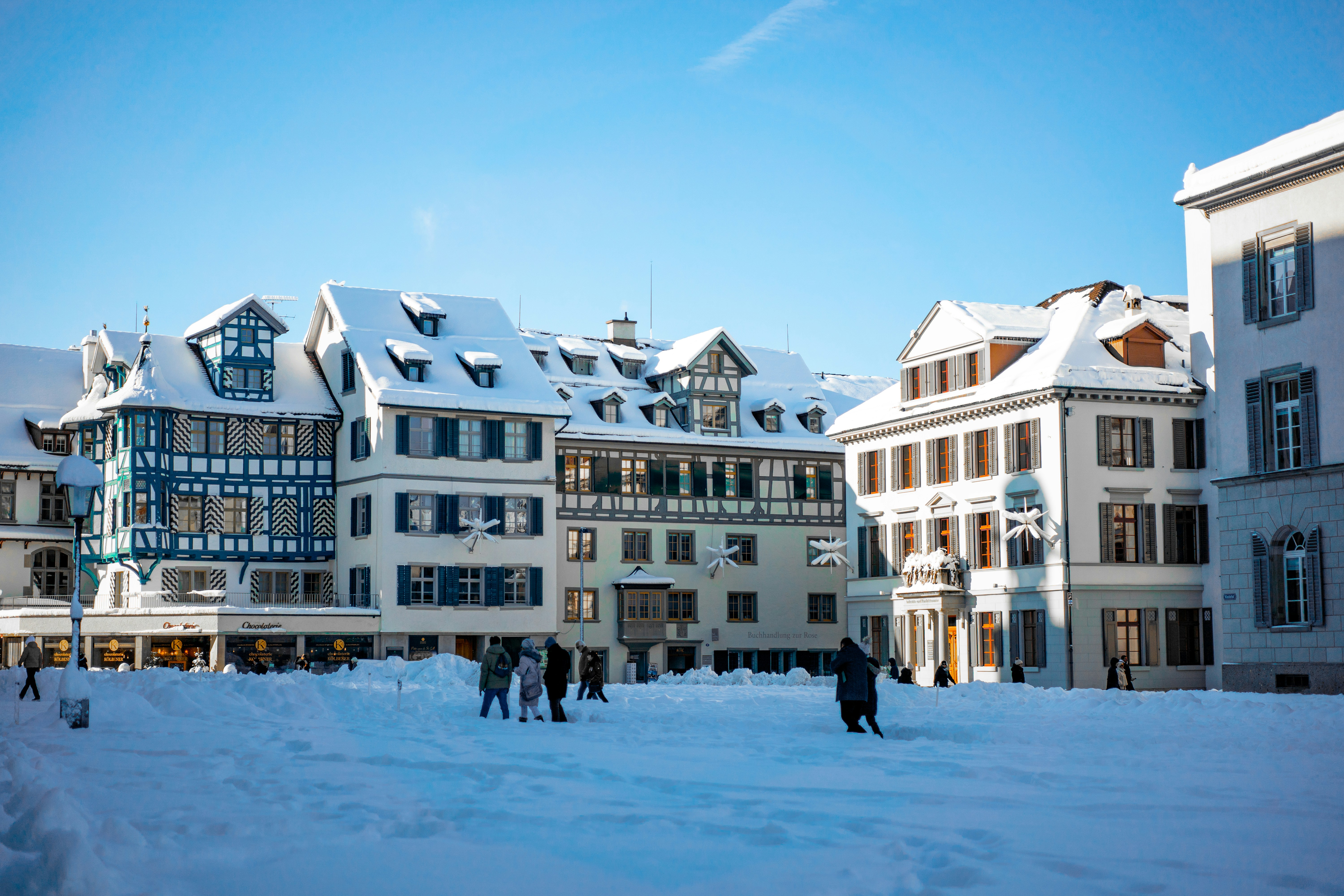 A group of people standing in the snow in front of a building photo ...