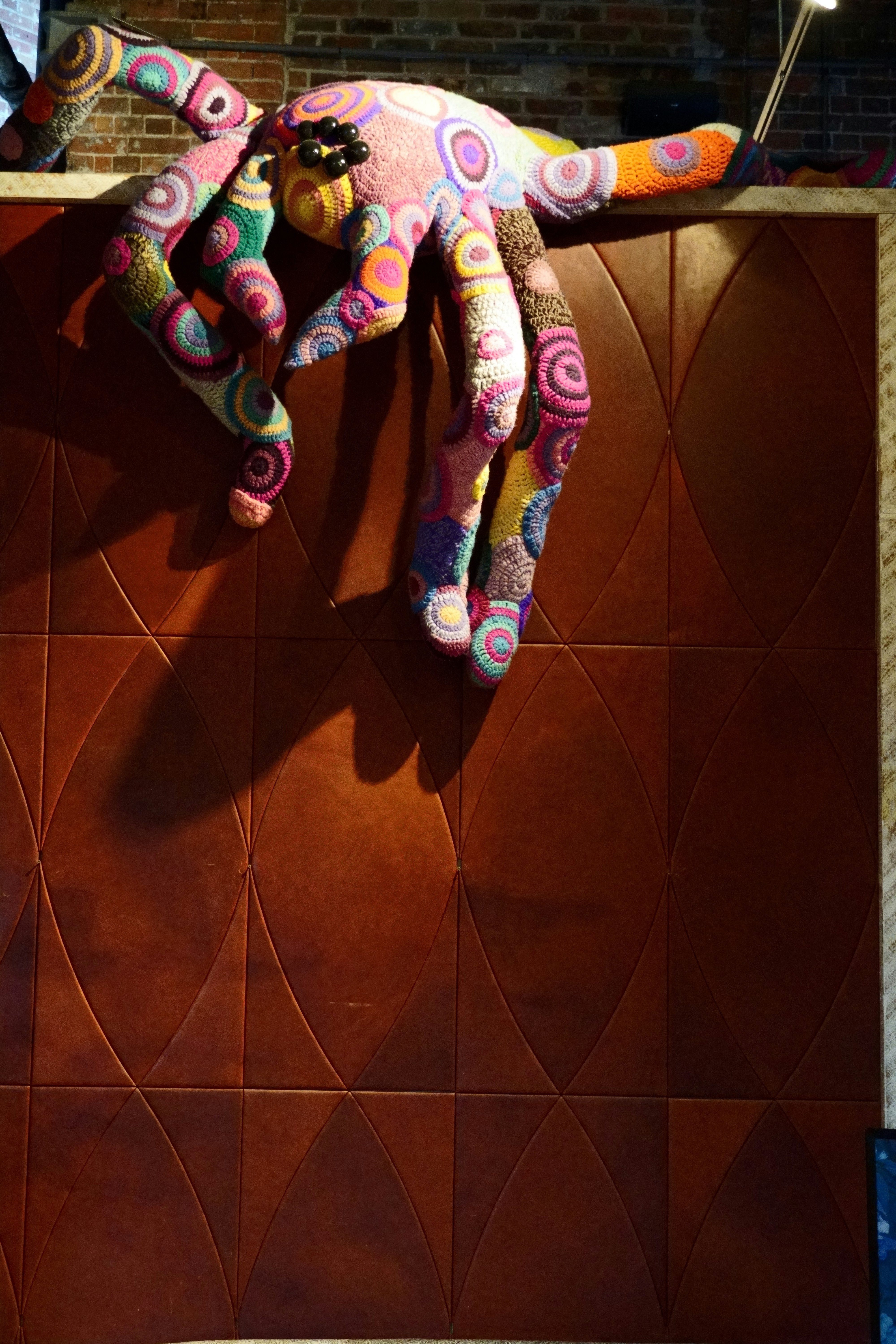Colorful Crochet Octopus Draped Across a Leather-Paneled Door