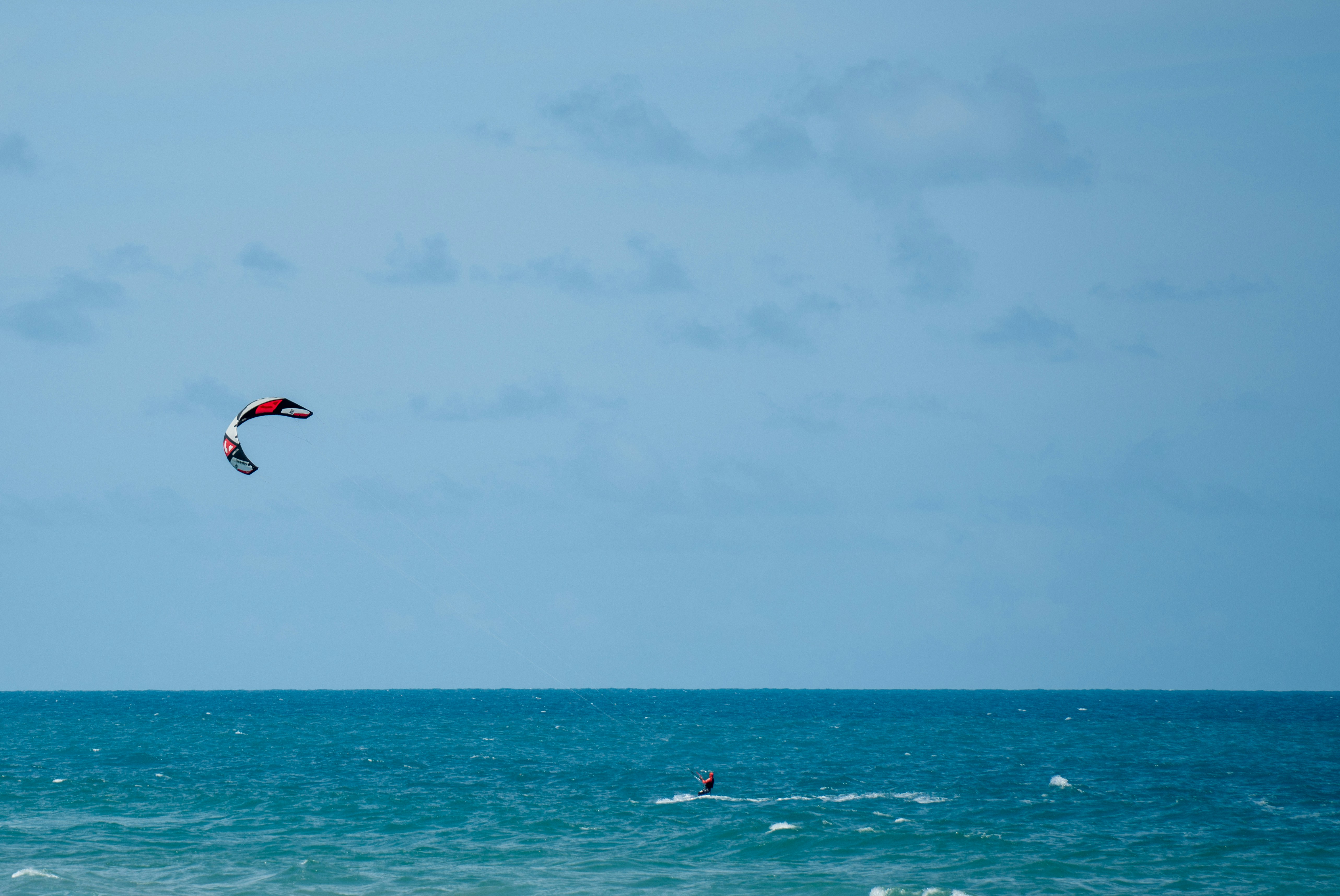 Red-White Kite Carving an Arc Across Turquoise Seas