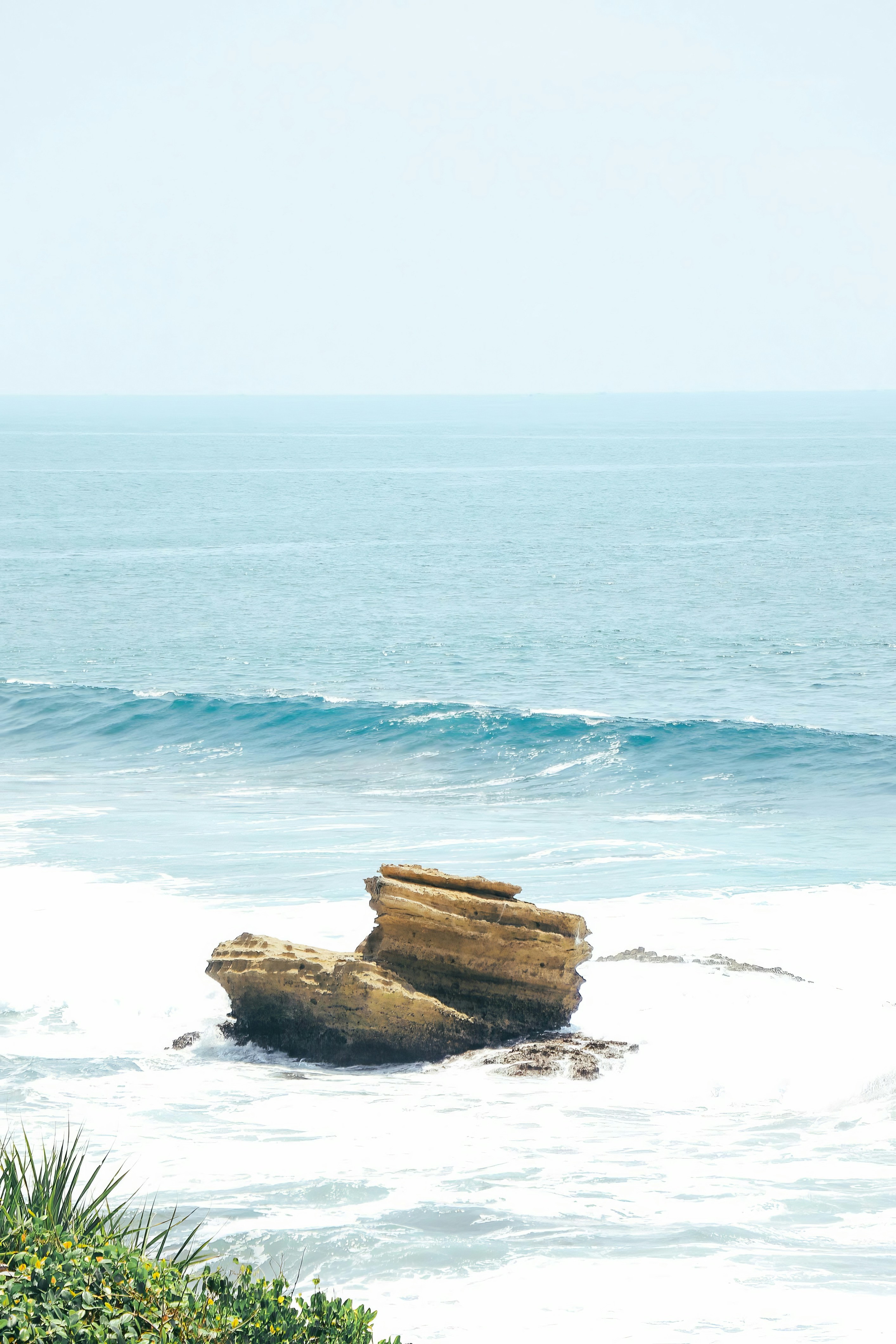A large rock sitting on top of a beach next to the ocean photo – Free ...