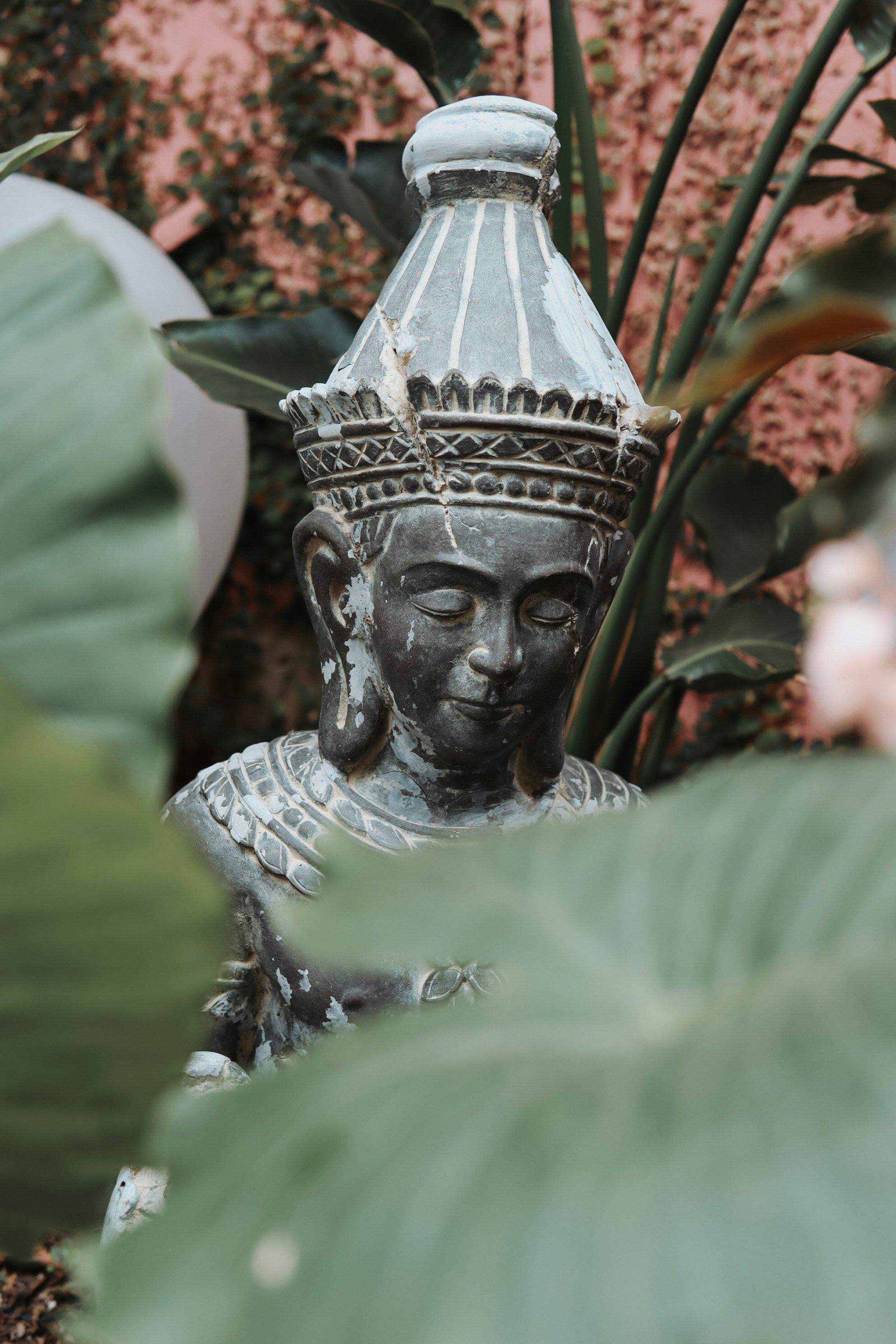 Weathered Buddha Amid Giant Garden Leaves