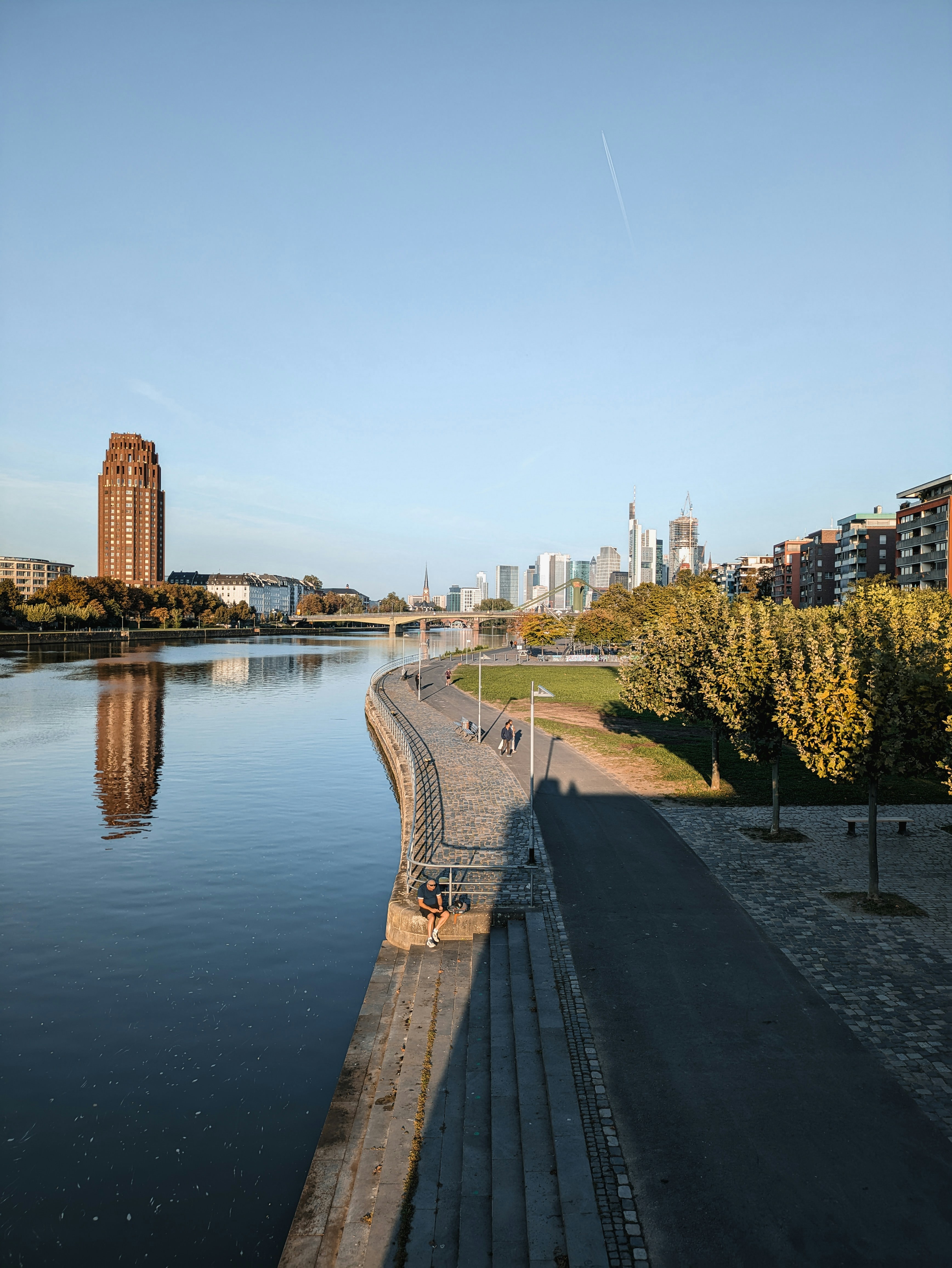 Riverside Horizon: A Curved Walk Toward a Modern Skyline at Dusk