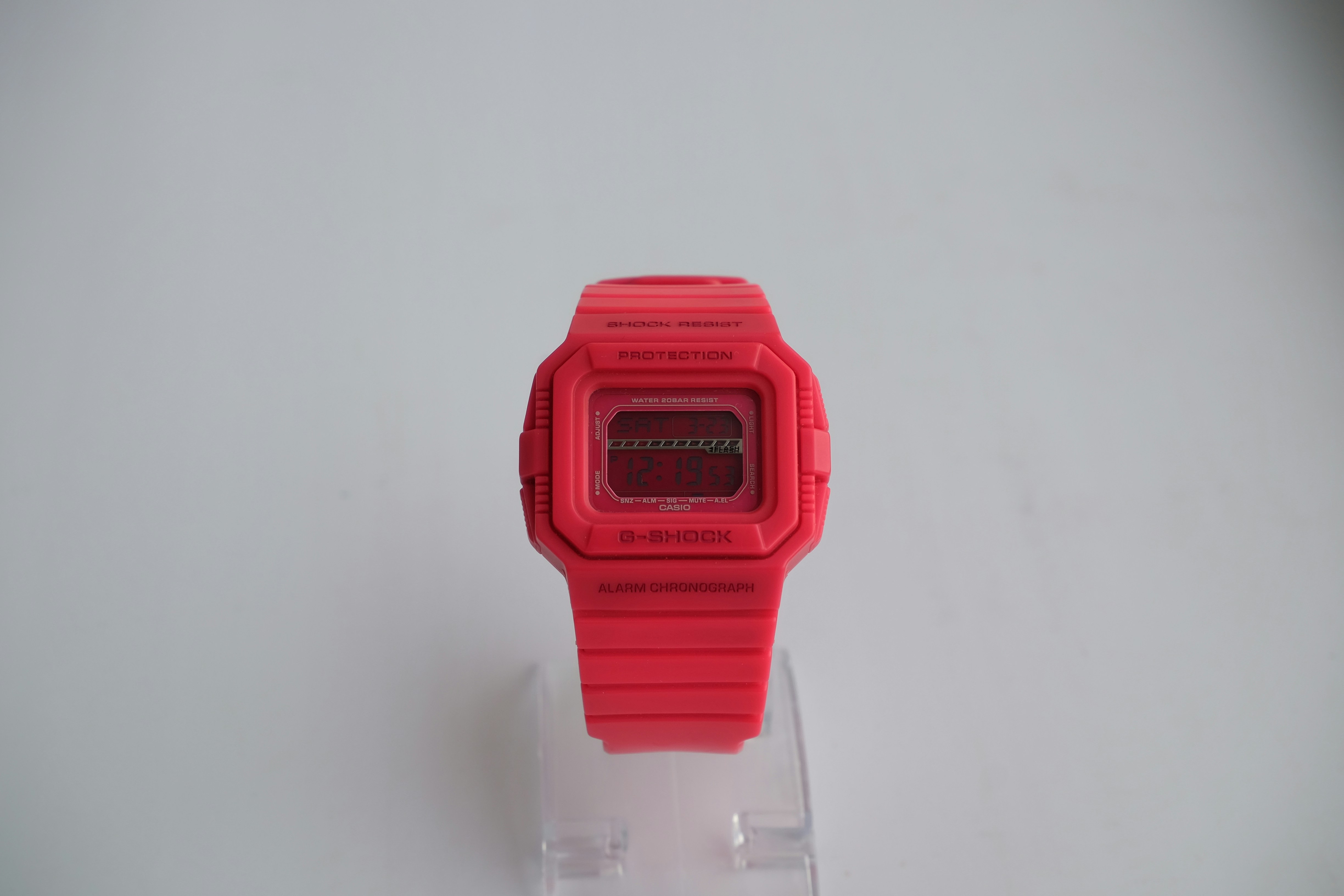 Scarlet Pulse: A Bold Red Digital Watch on a Clear Studio Stand