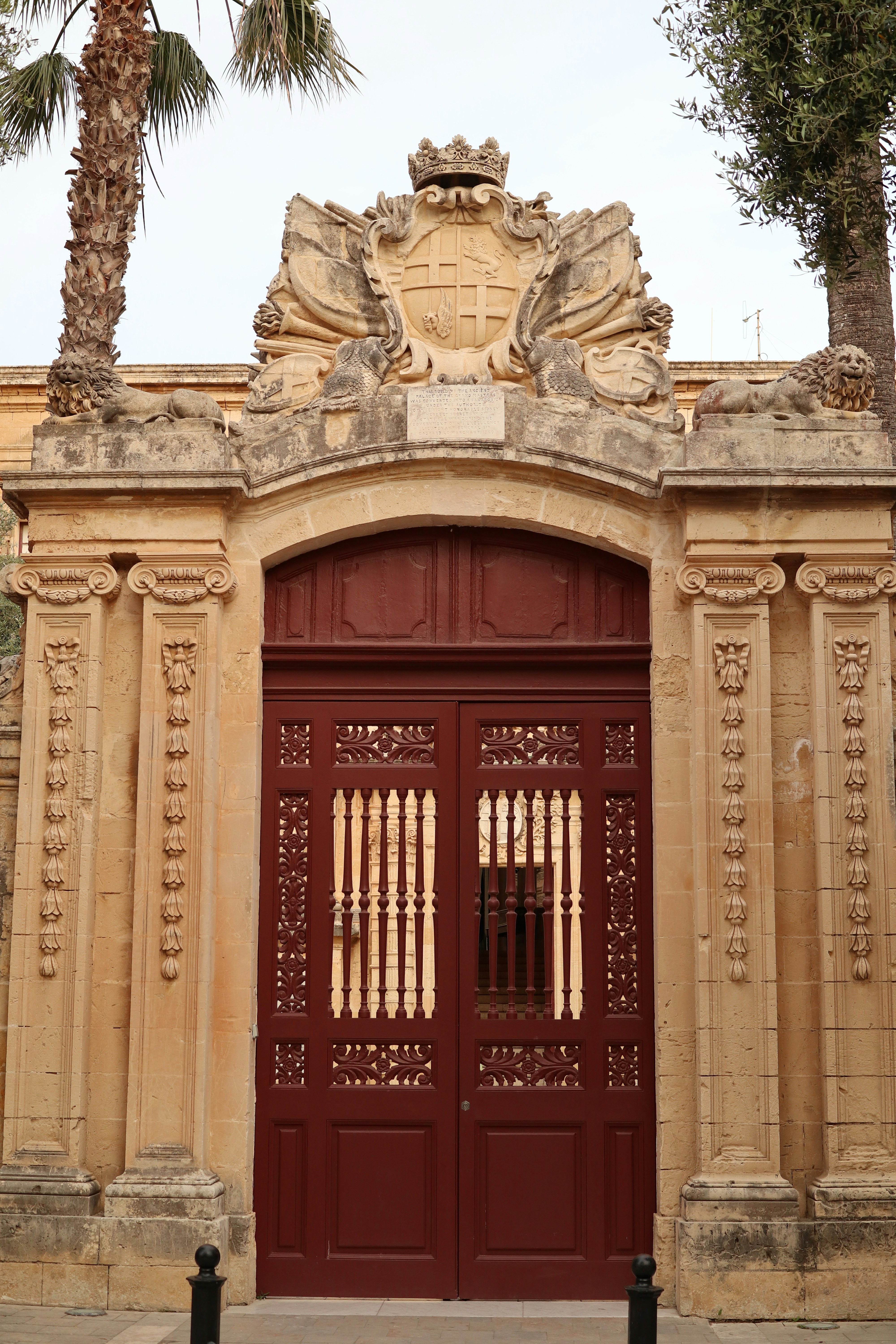 Sunlit Portal: Baroque Archway Framing a Crimson Gate