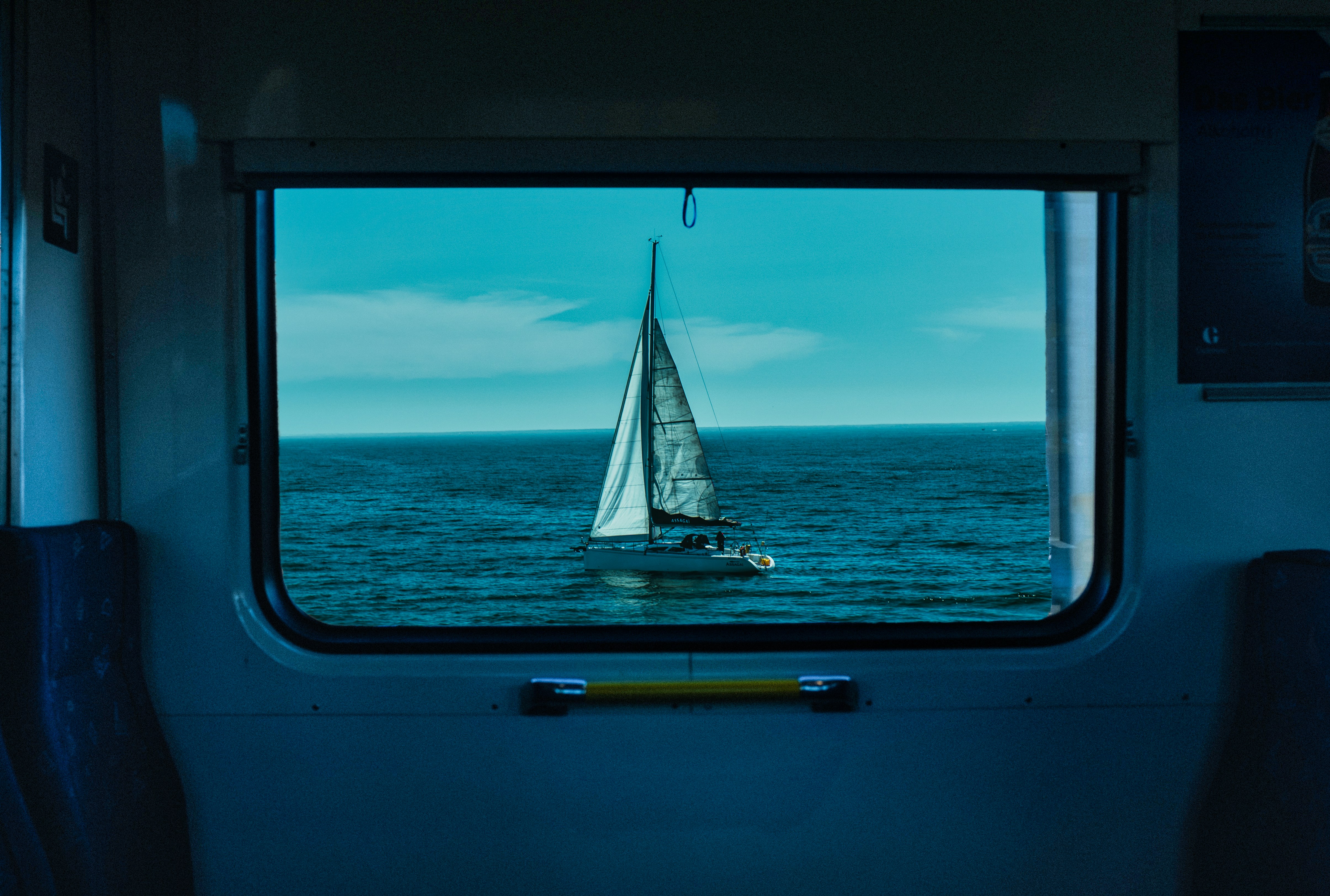 A sailboat sailing in the ocean through a window photo – Free Sea Image ...