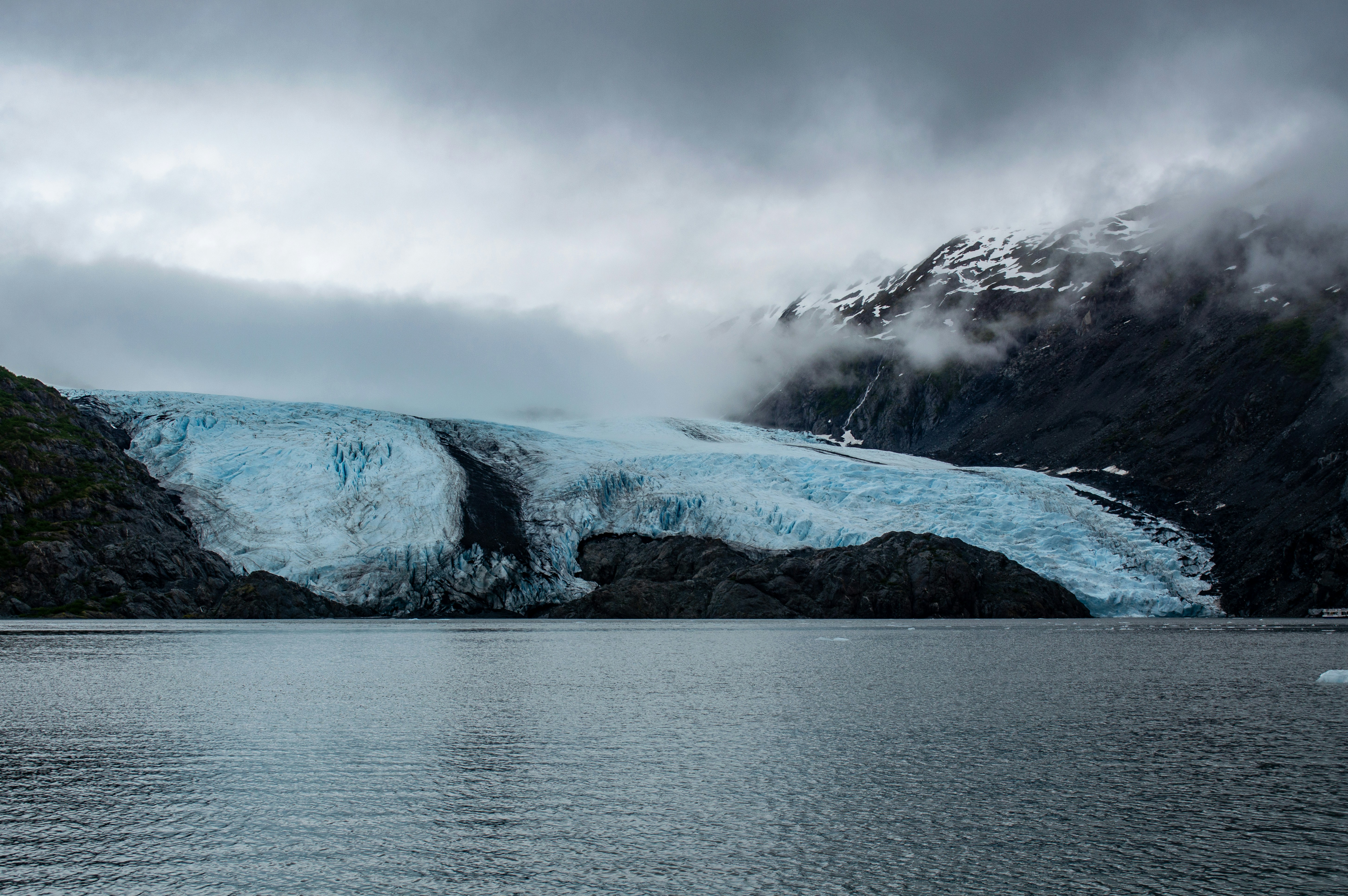 Expansive glacier cascading down a rugged mountain under a cloudy, dramatic sky.