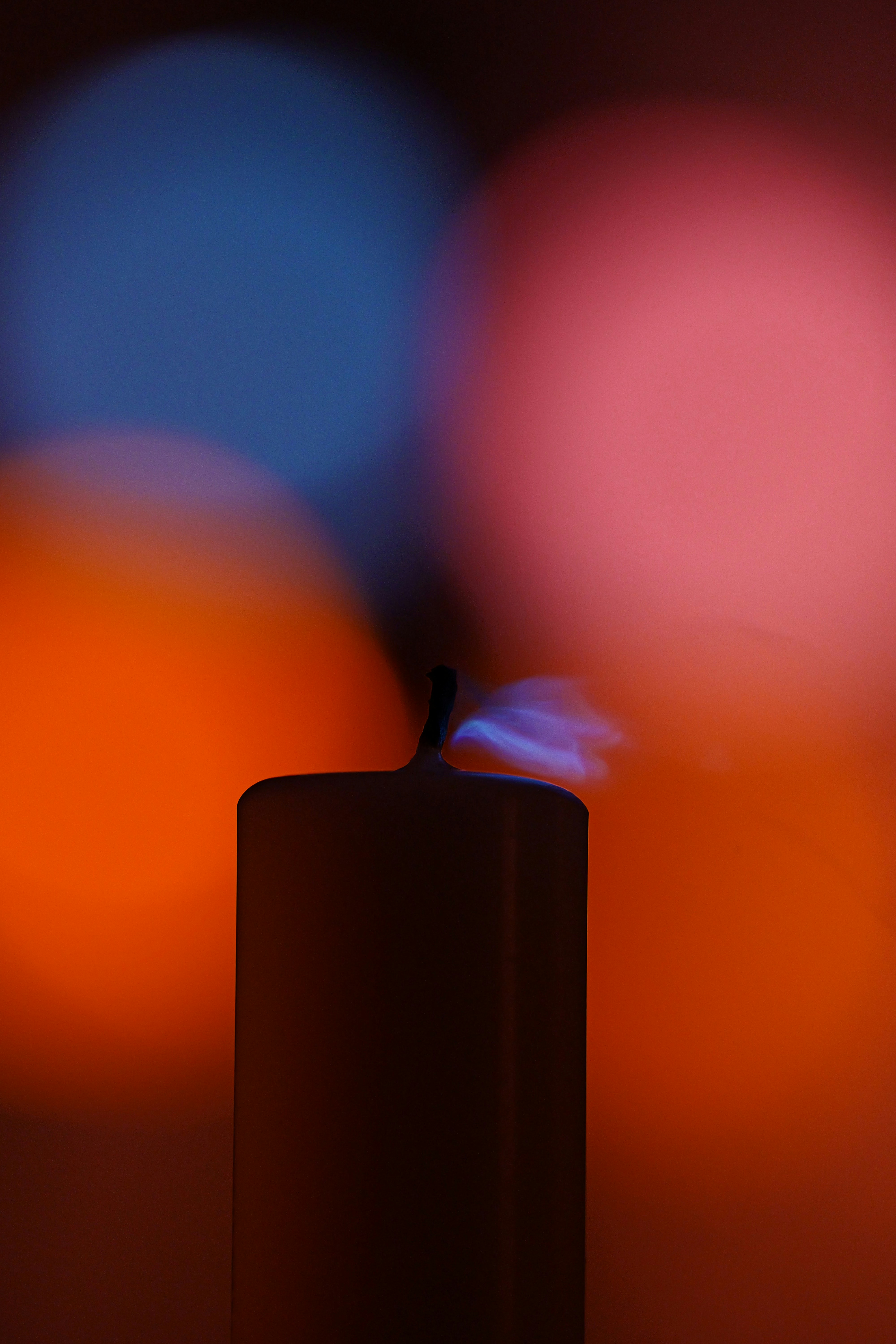Silhouetted Candle Against Neon Blurs