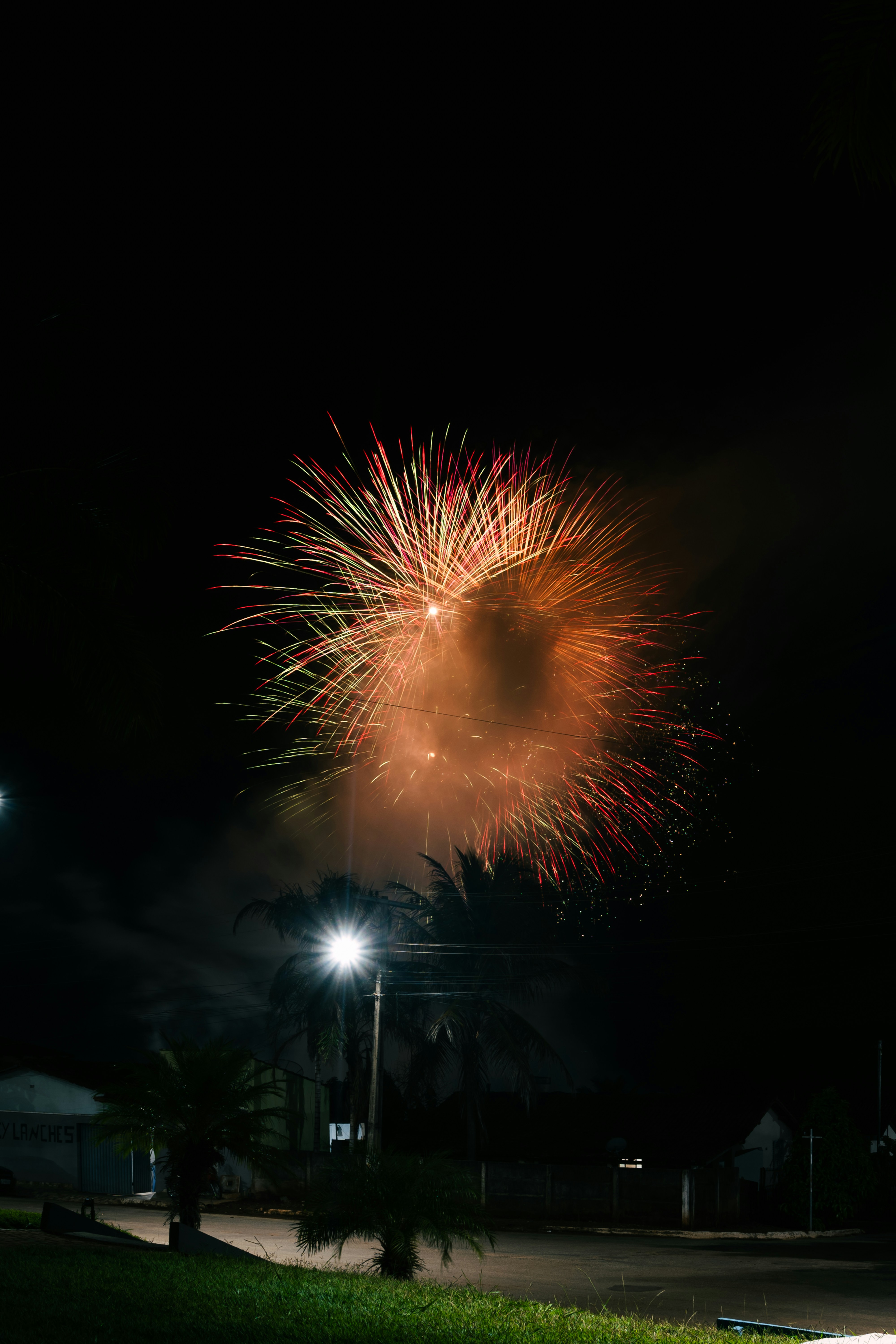 Fireburst Above a Palm-Lined Night Street