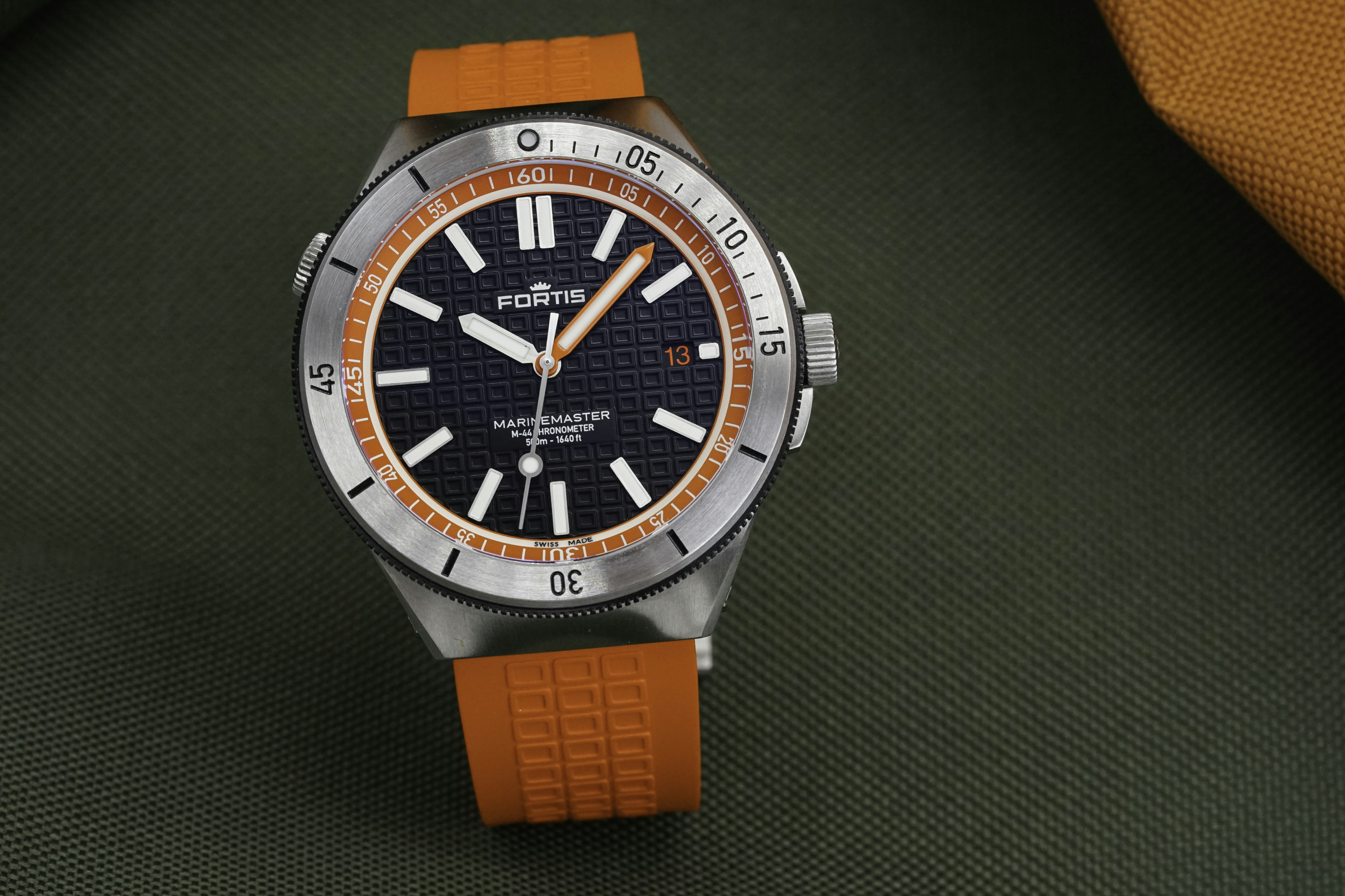 Fortis Navigator: Orange Strap Framing a Precision Dial on Olive Textures