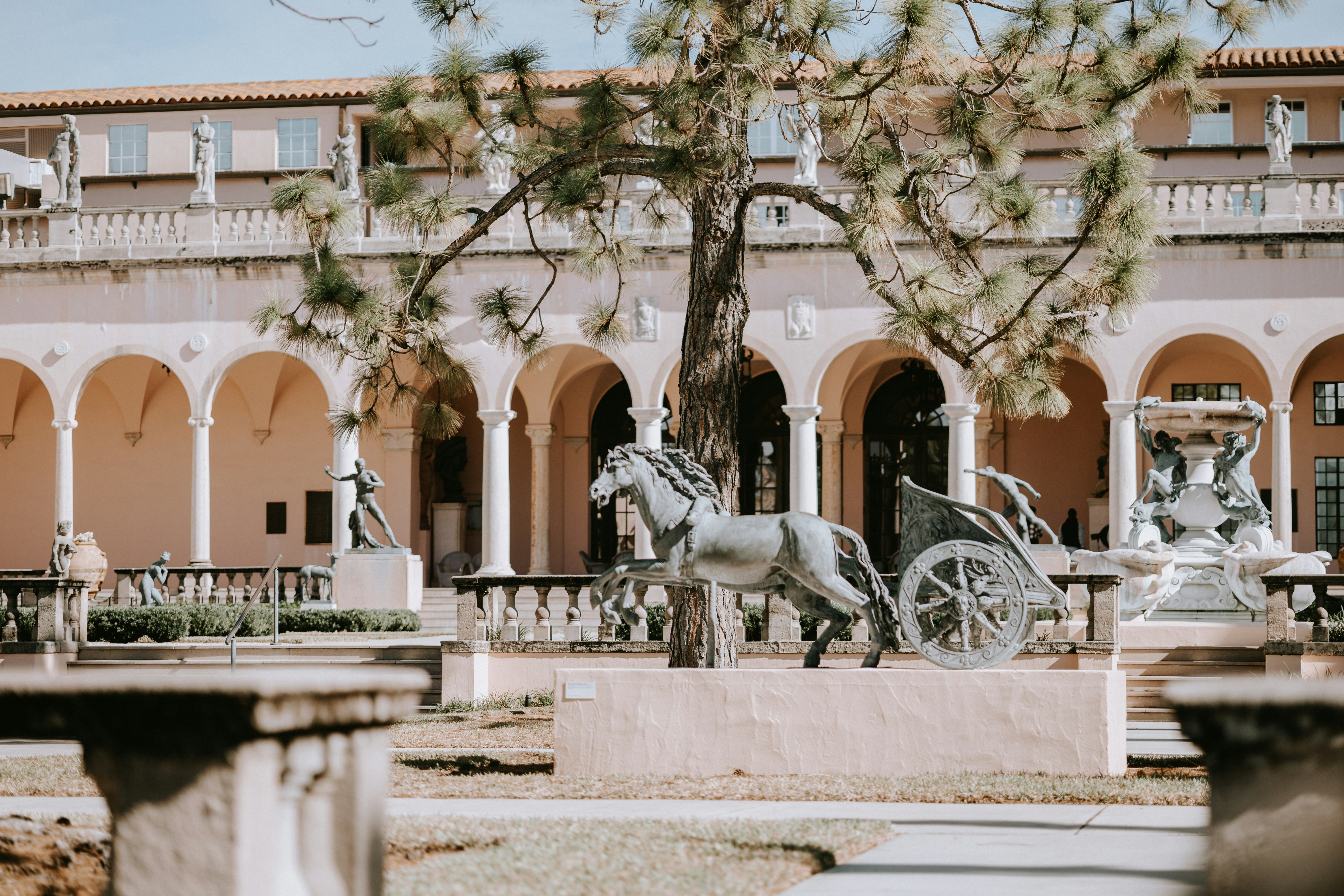 A statue of a horse drawn carriage in front of a building photo – Free ...