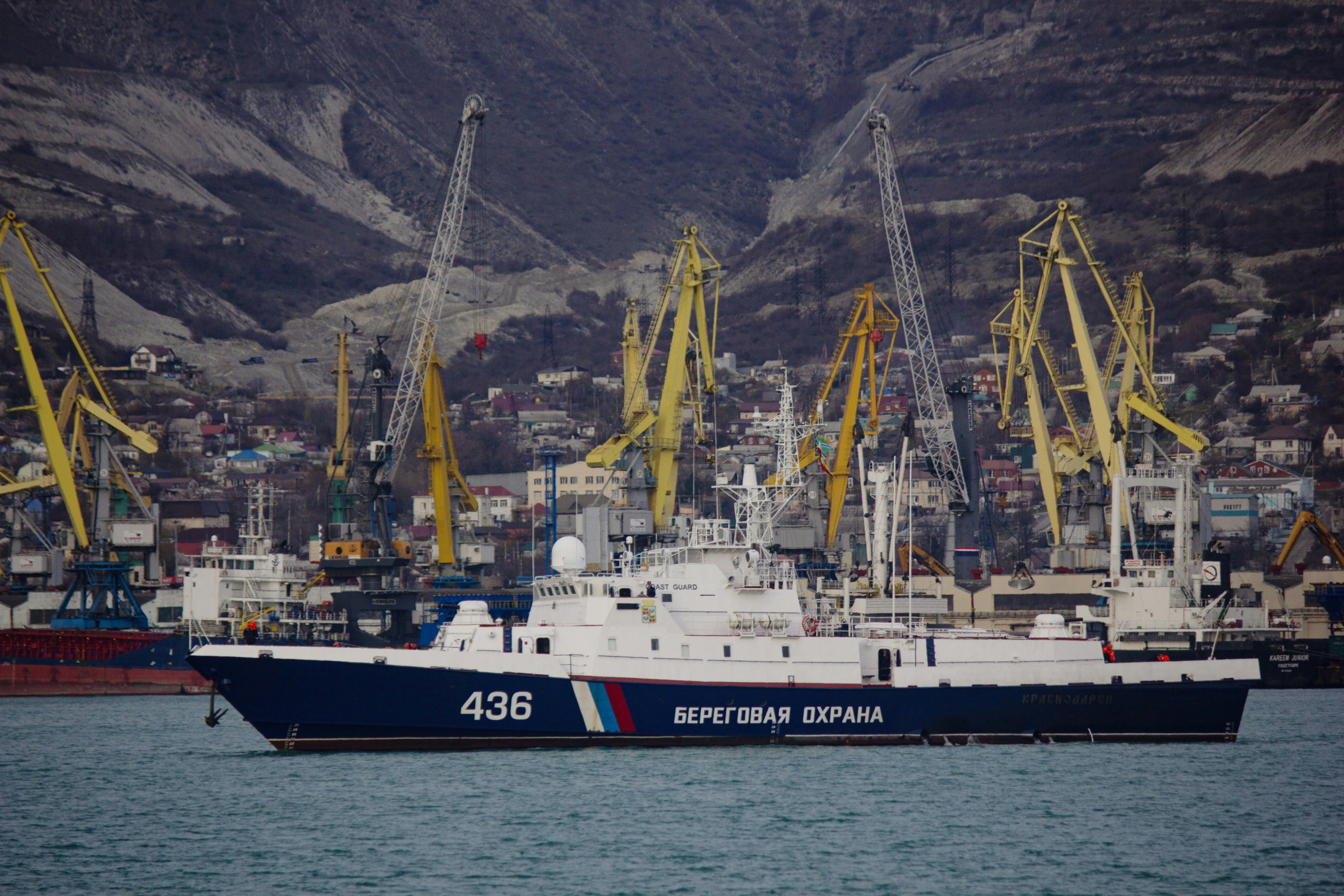 436 at the Dock: Coast Guard Vessel Framed by Yellow Cranes and a Mountain Backdrop