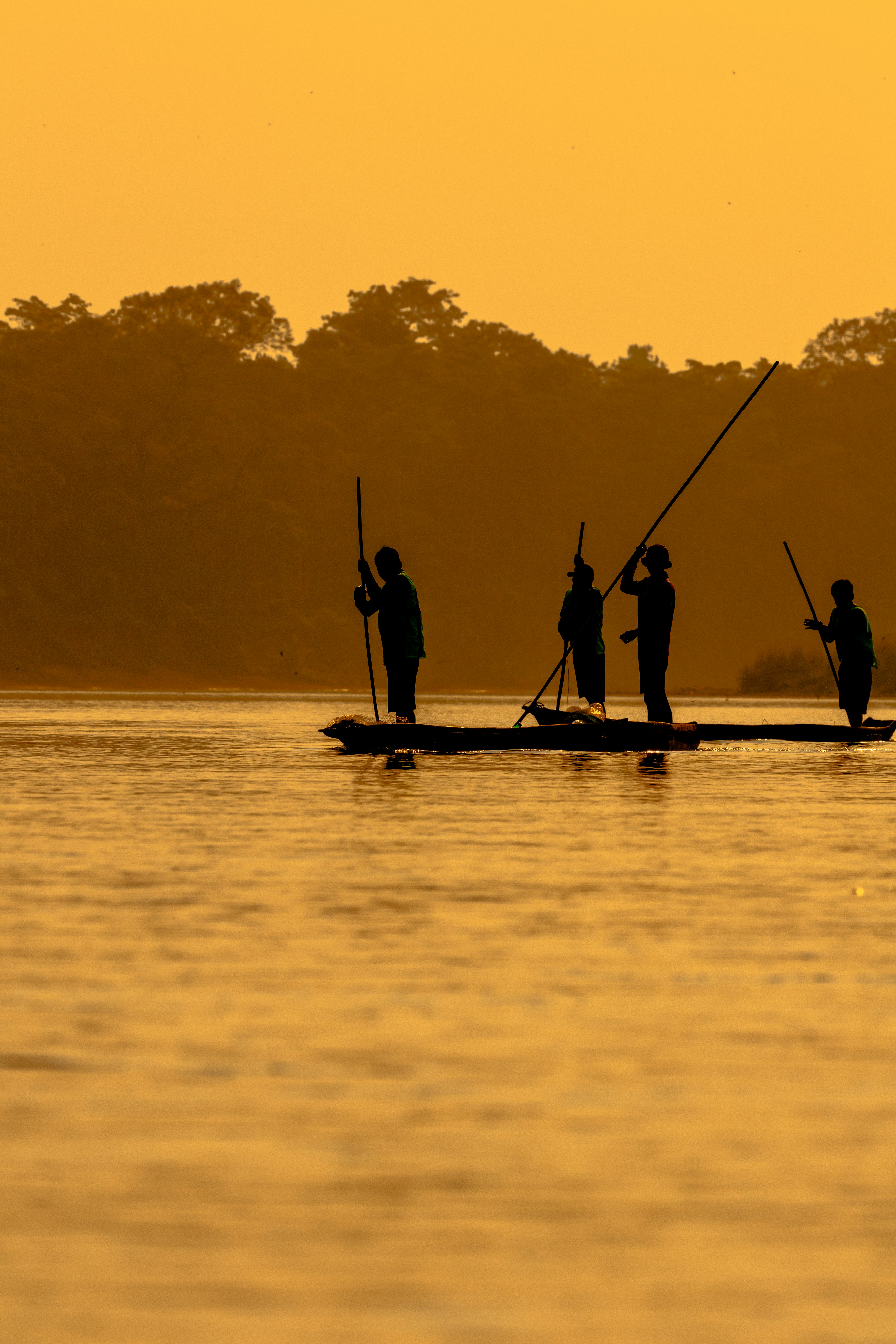 Gold Horizon Anglers: Four Silhouettes on a River Raft at Dusk