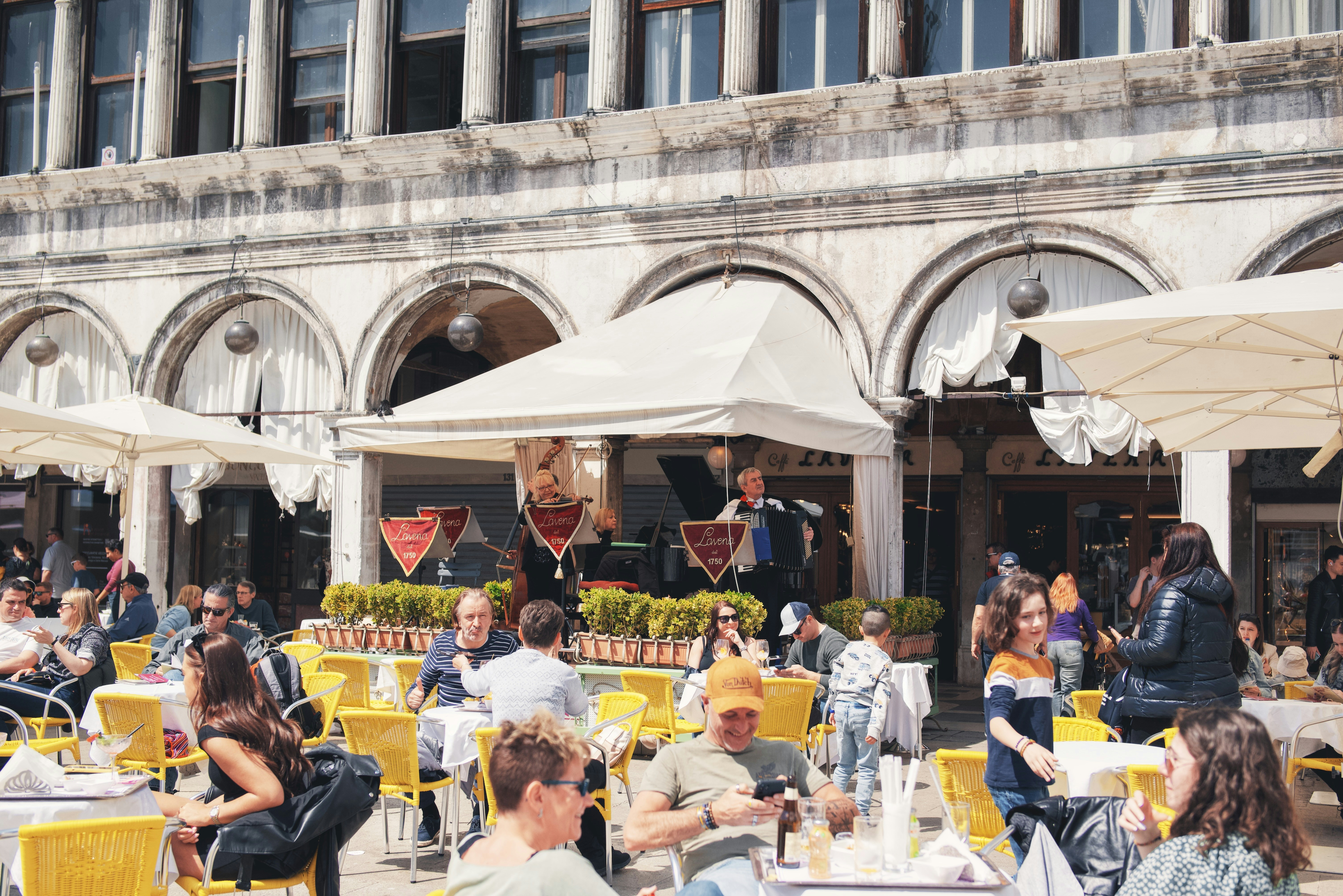 Yellow-Chair Café: Sunlit chatter beneath arched facades
