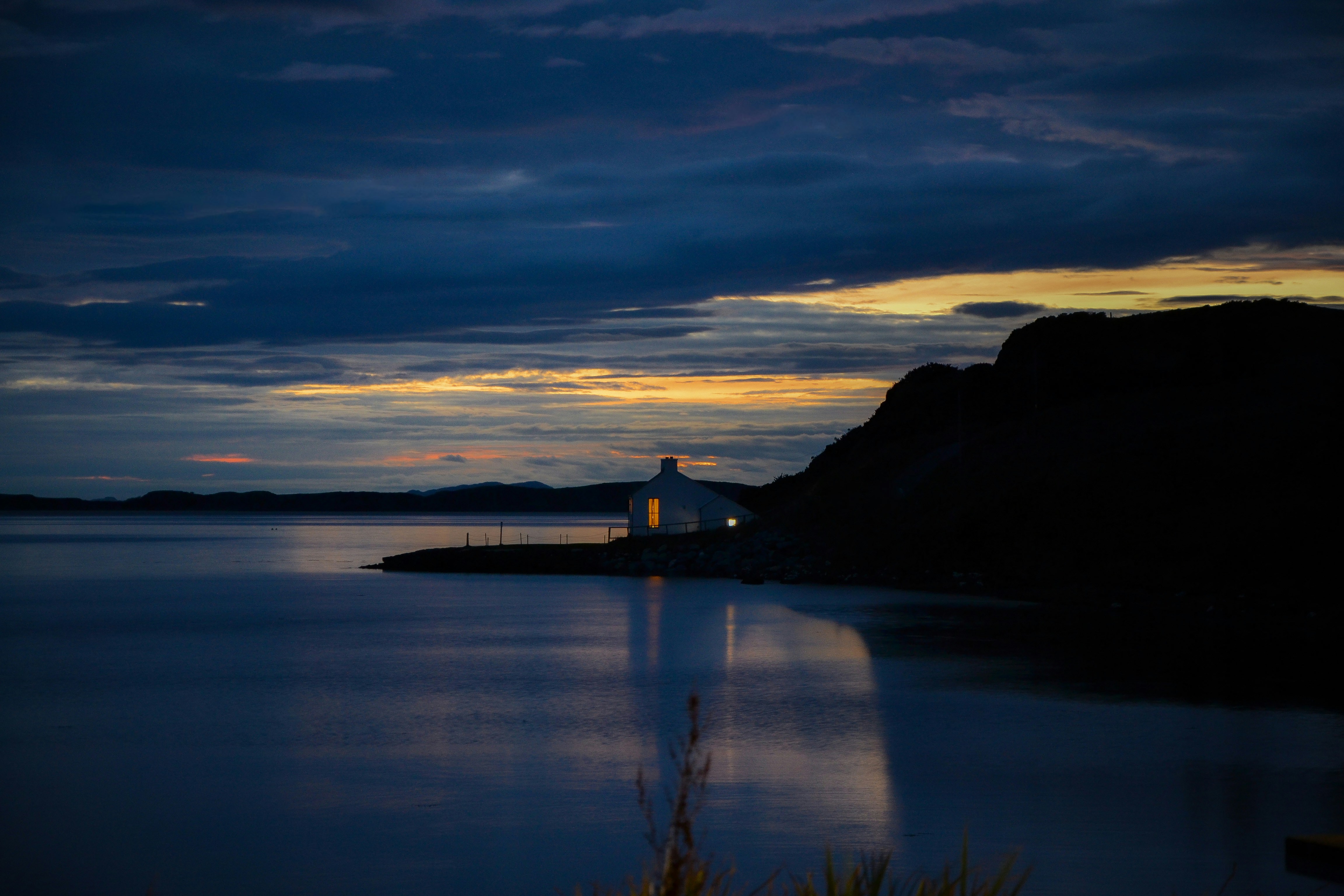 Blue Hour Beacon: A solitary house at the edge of a calm harbor