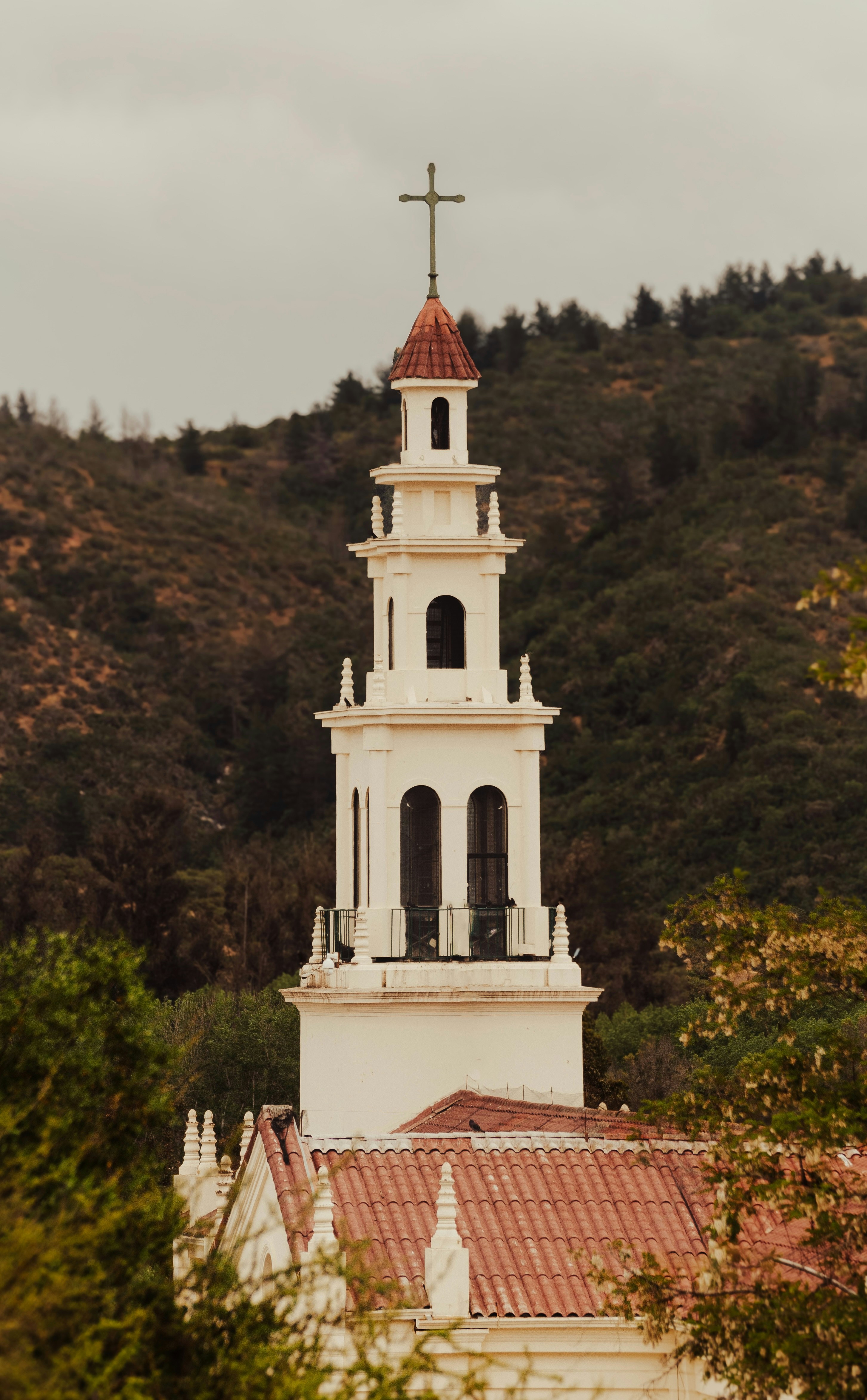 Bell Tower Rising Over Red-Tiled Roofs and Pine Hills