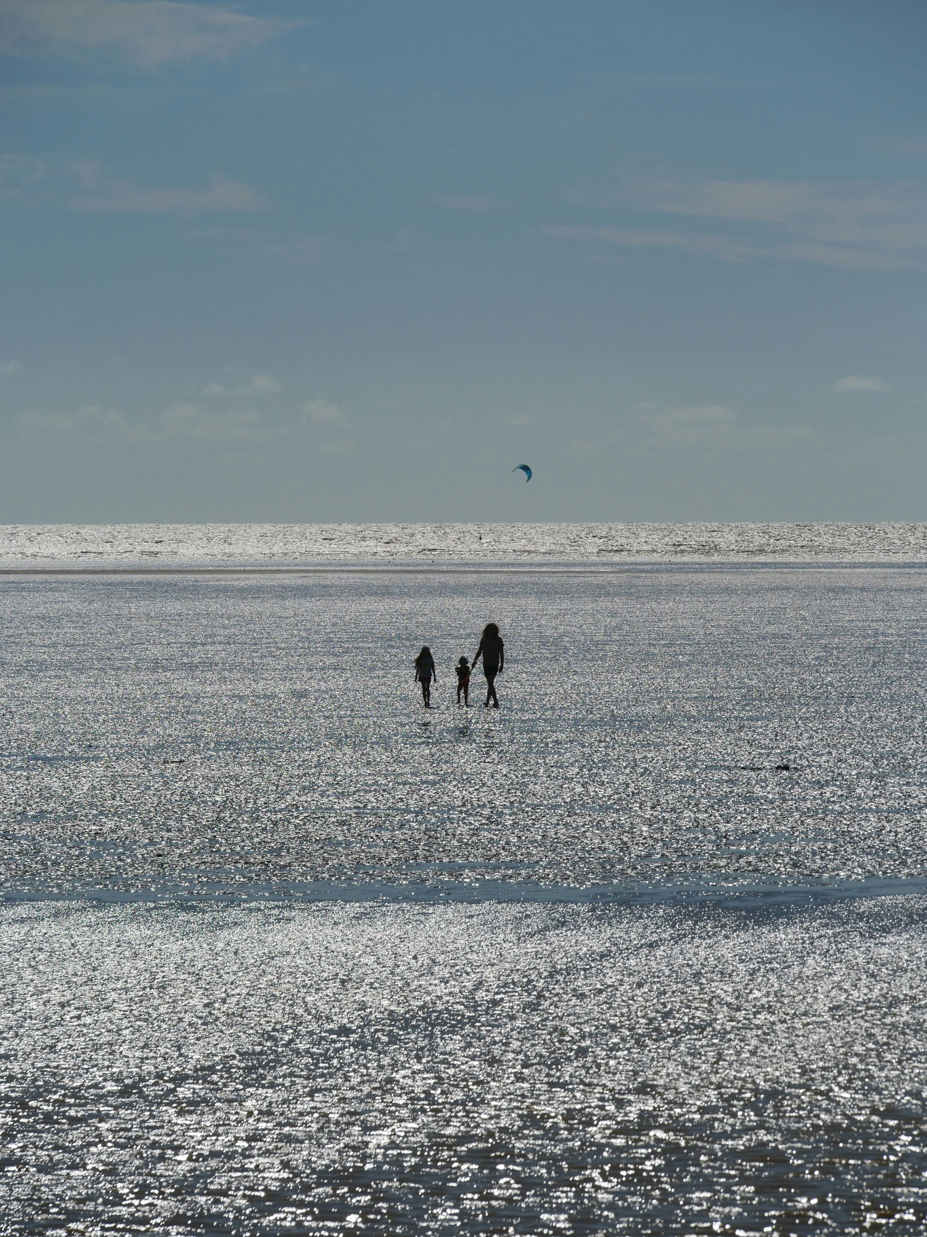 Kite traveler: silhouettes silhouette against glimmering shoreline
