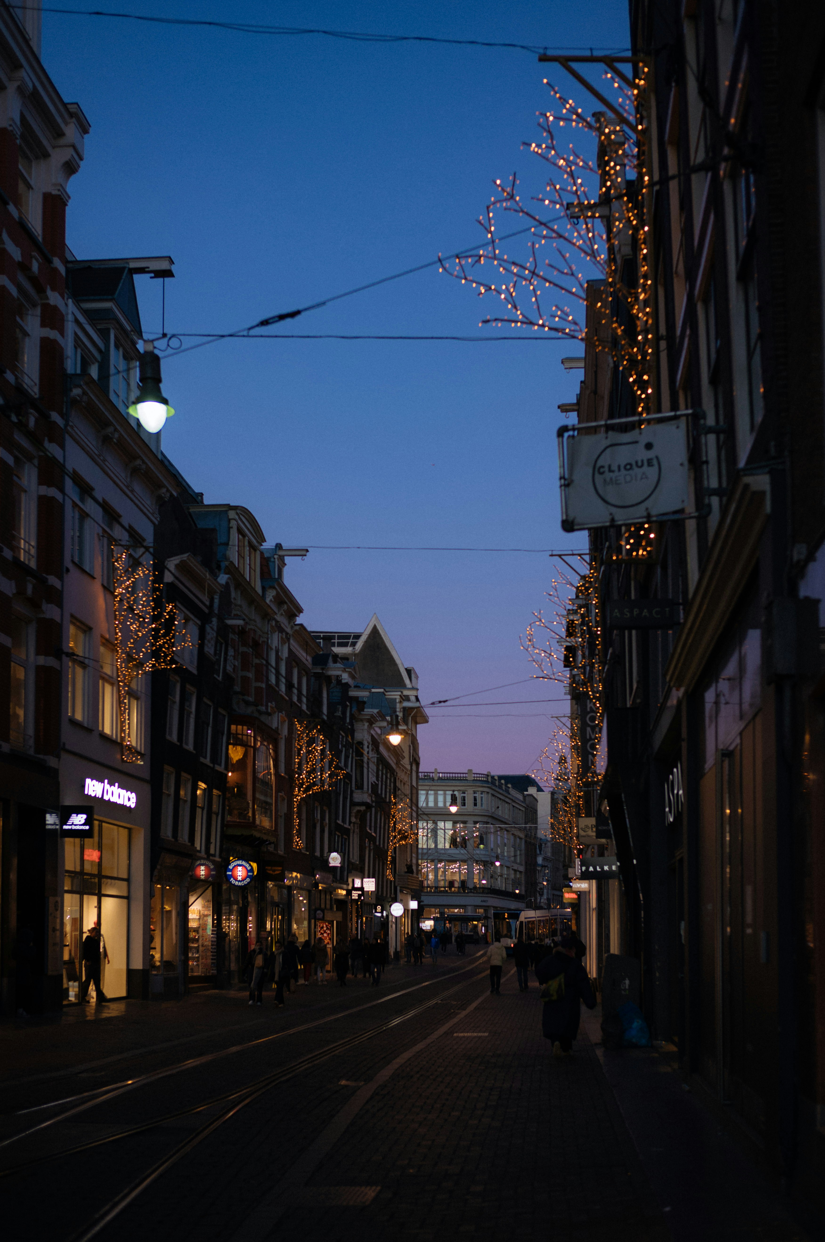 Evening street scene with glowing lights and deep blue sky at dusk.