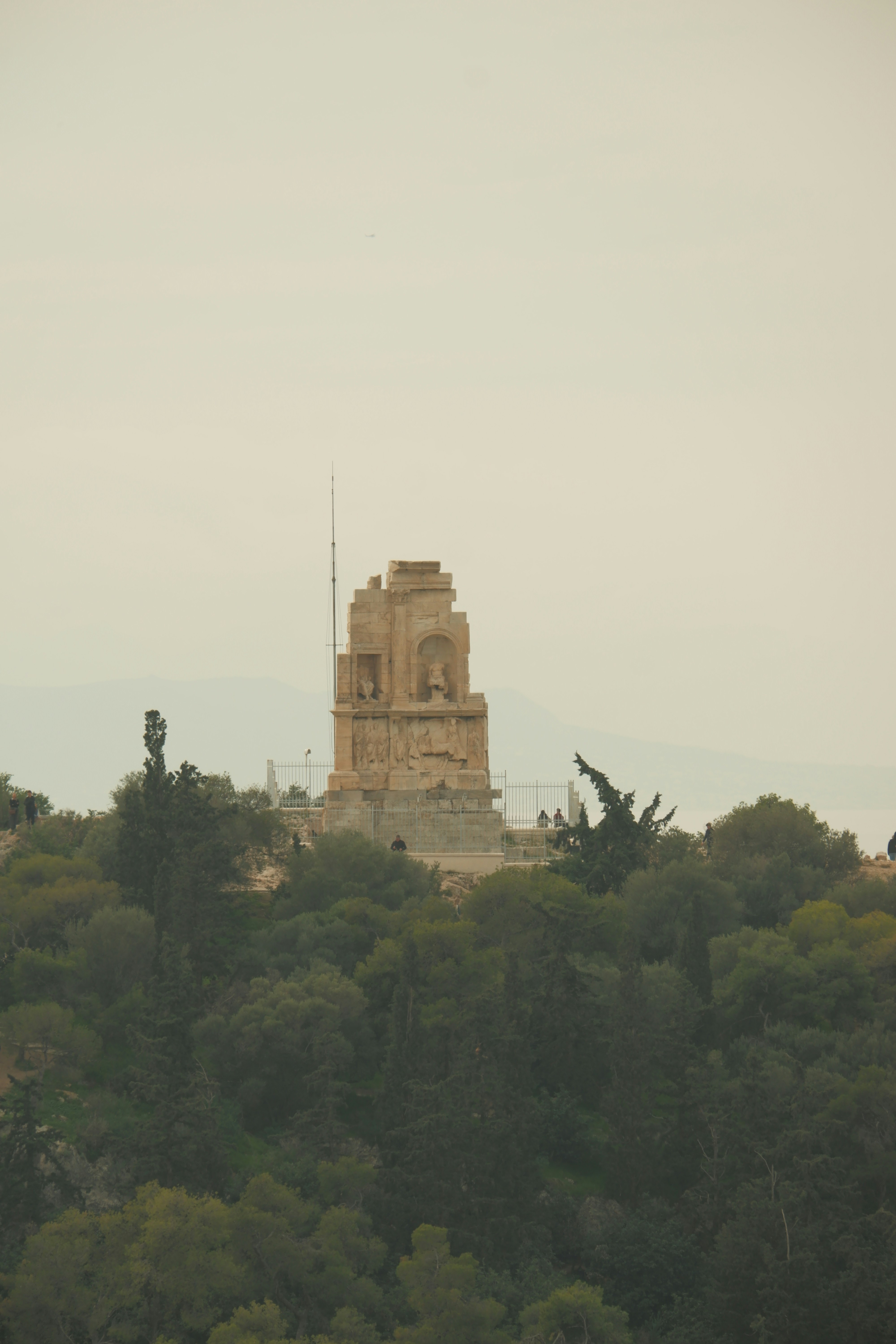 Hilltop Relic in Mist: A solitary monument crowns the forested slope