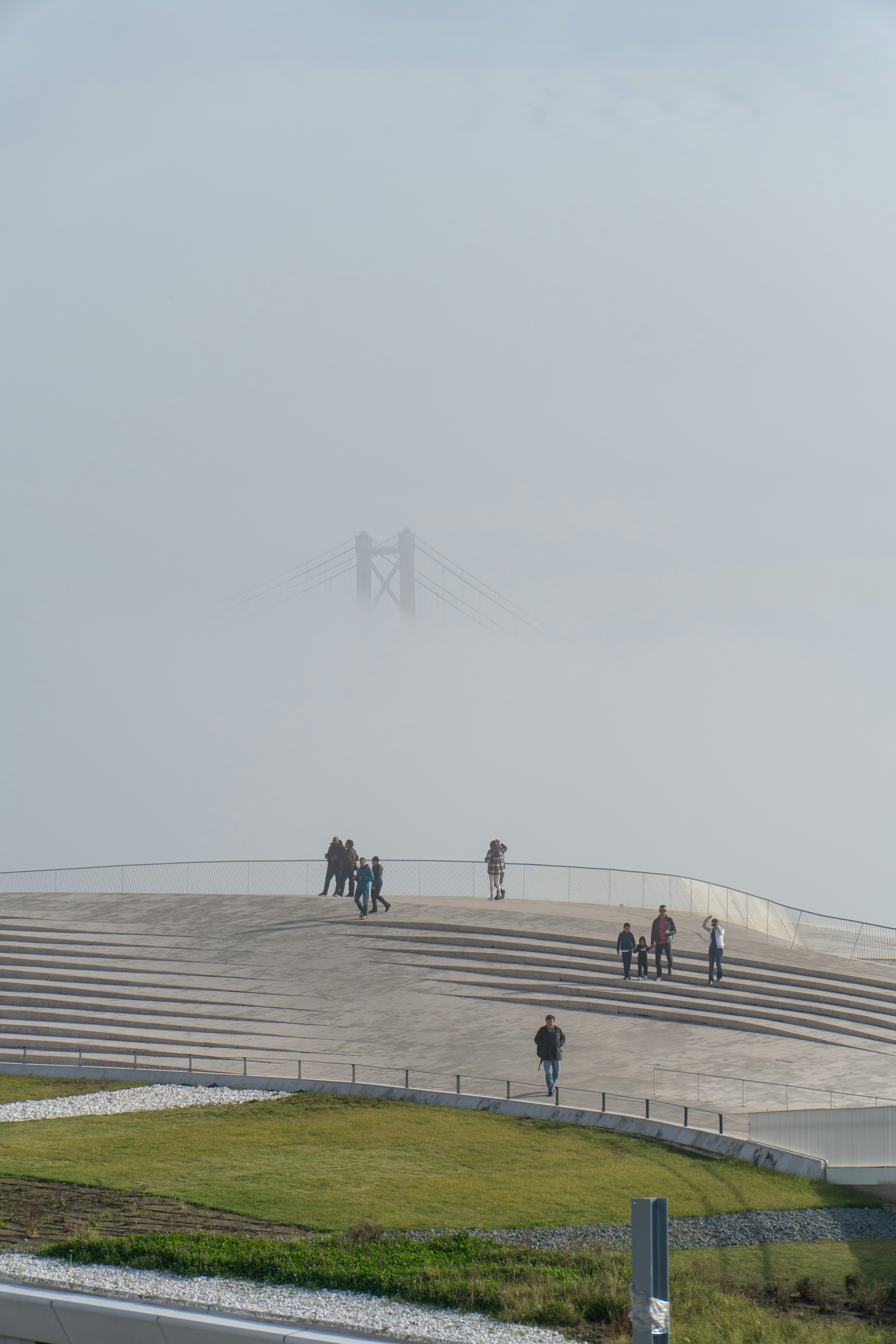 Mistbound Promenade: People Climb Toward a Ghostly Suspension Bridge