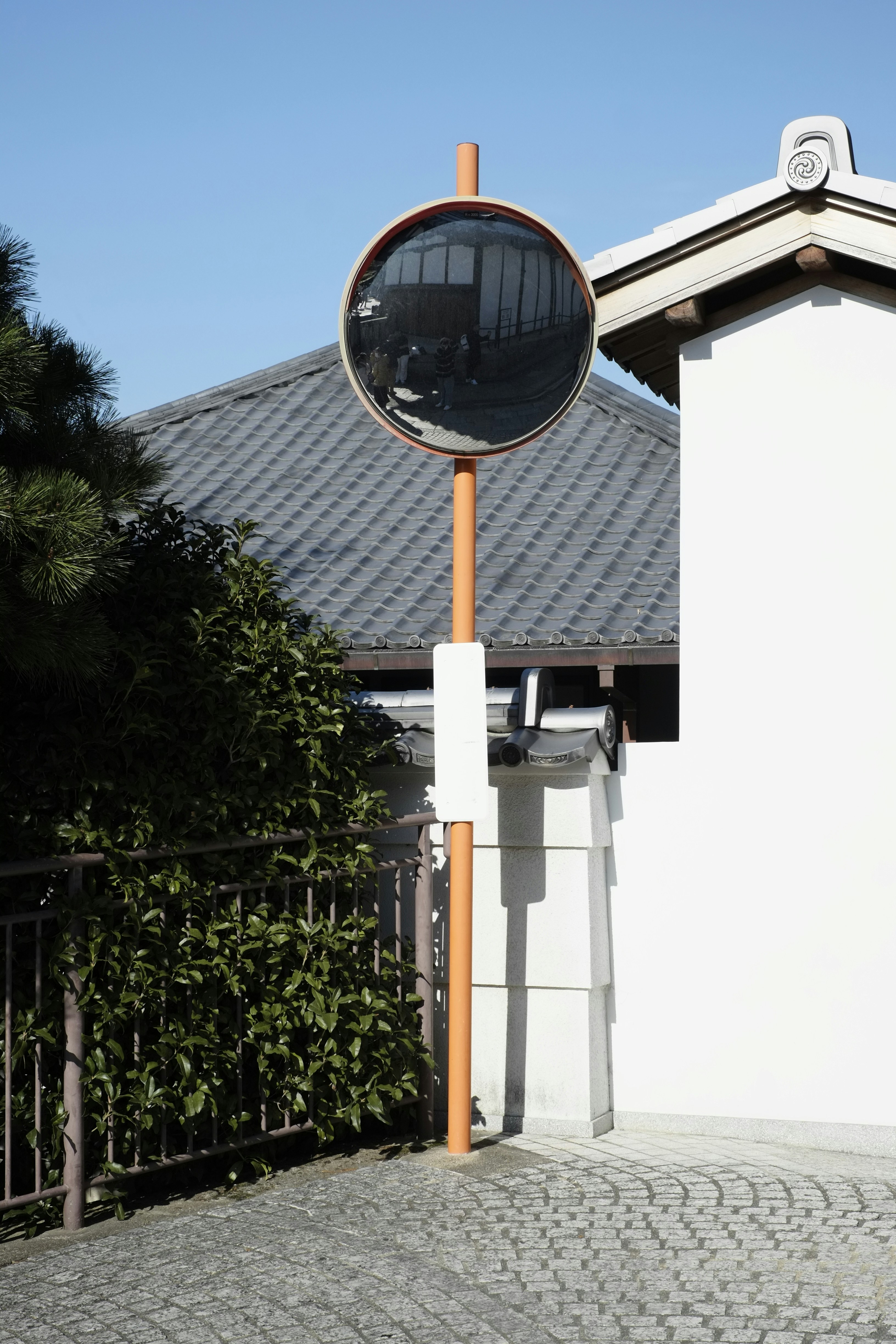 Convex Mirror on an Orange Post Framing a Quiet Japanese Courtyard