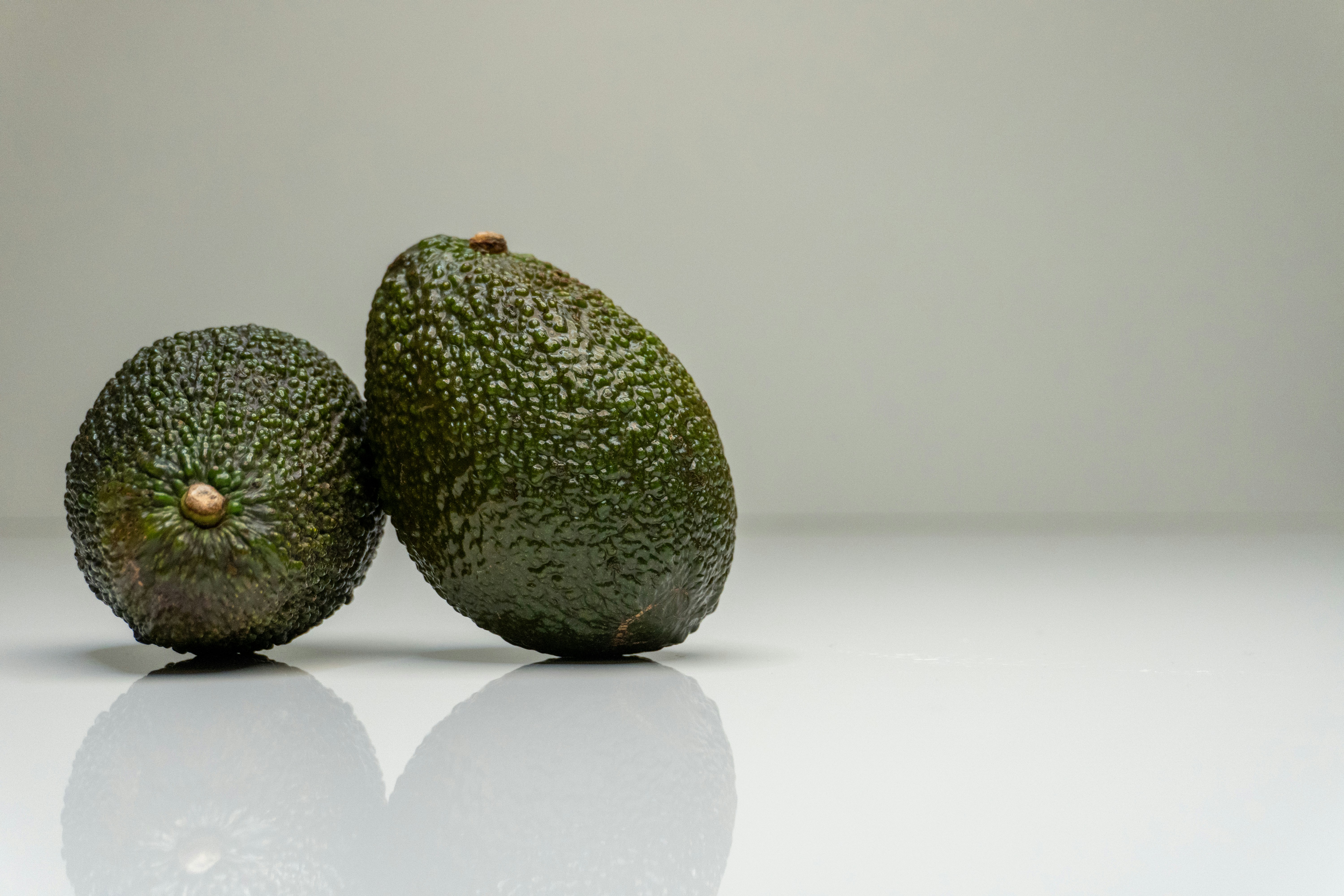 Two avocados sitting side by side on a white surface photo – Free ...