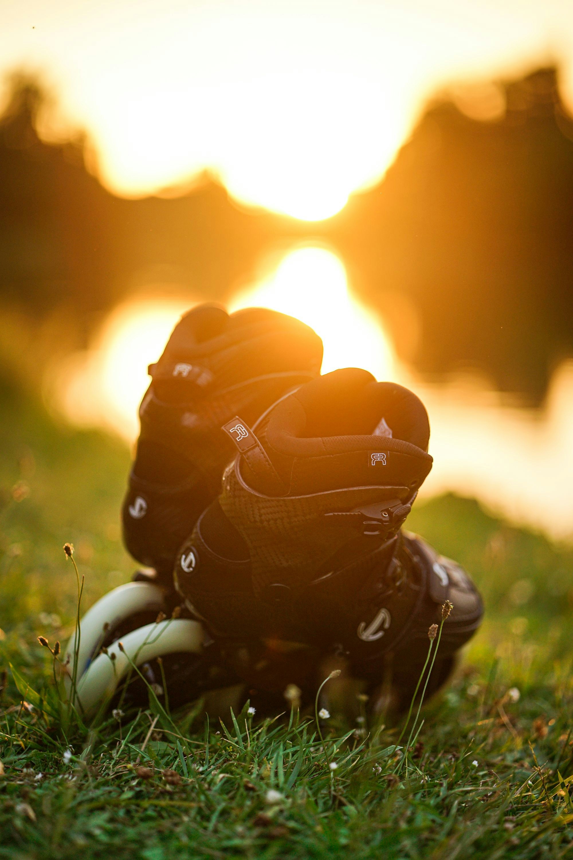Golden Hour Rest: Rollerblades on Grassy Shore by a Glowing Lake
