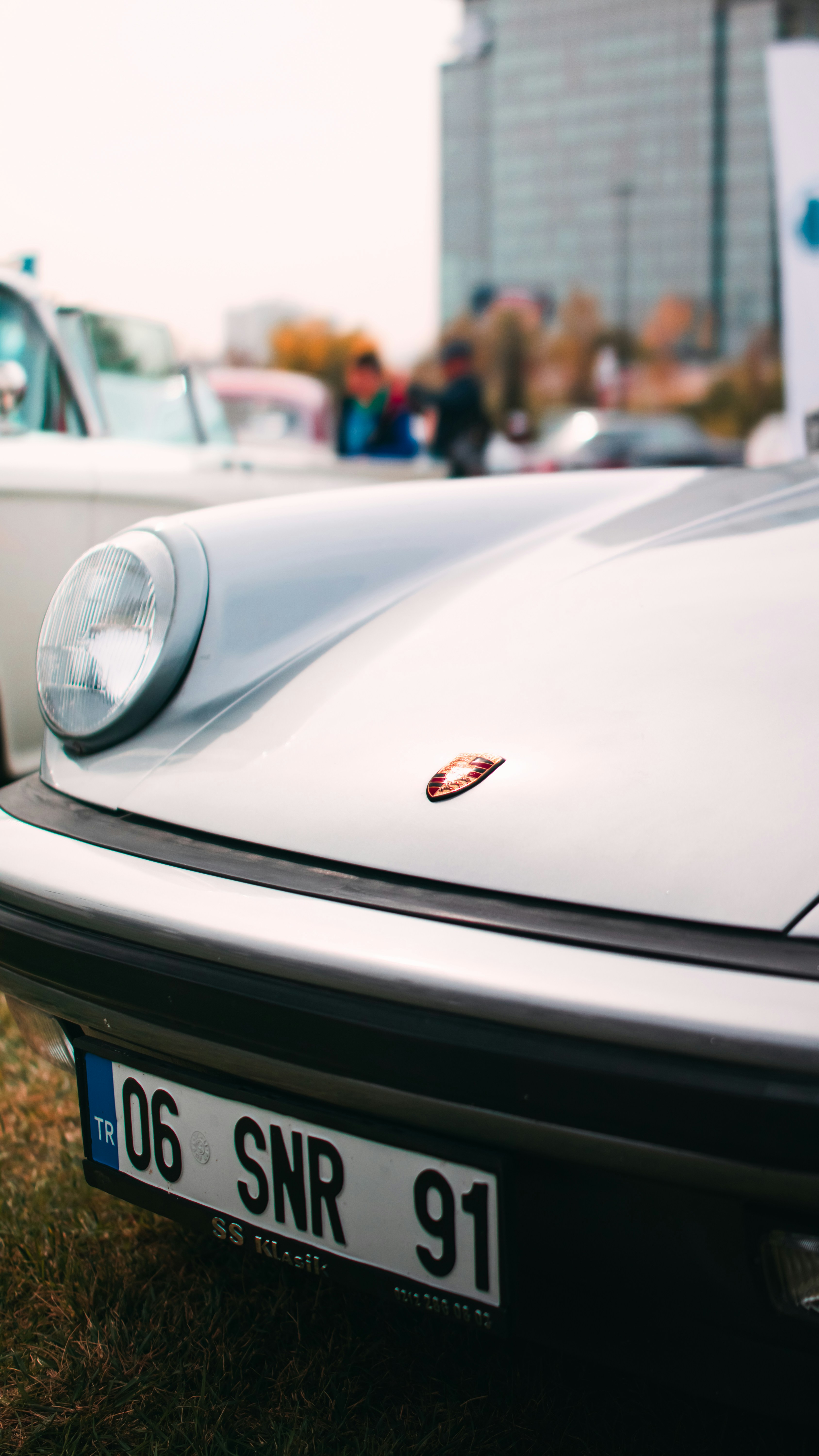 Chrome Badge, Headlight Edge: A Classic Porsche Stares from the Car Show