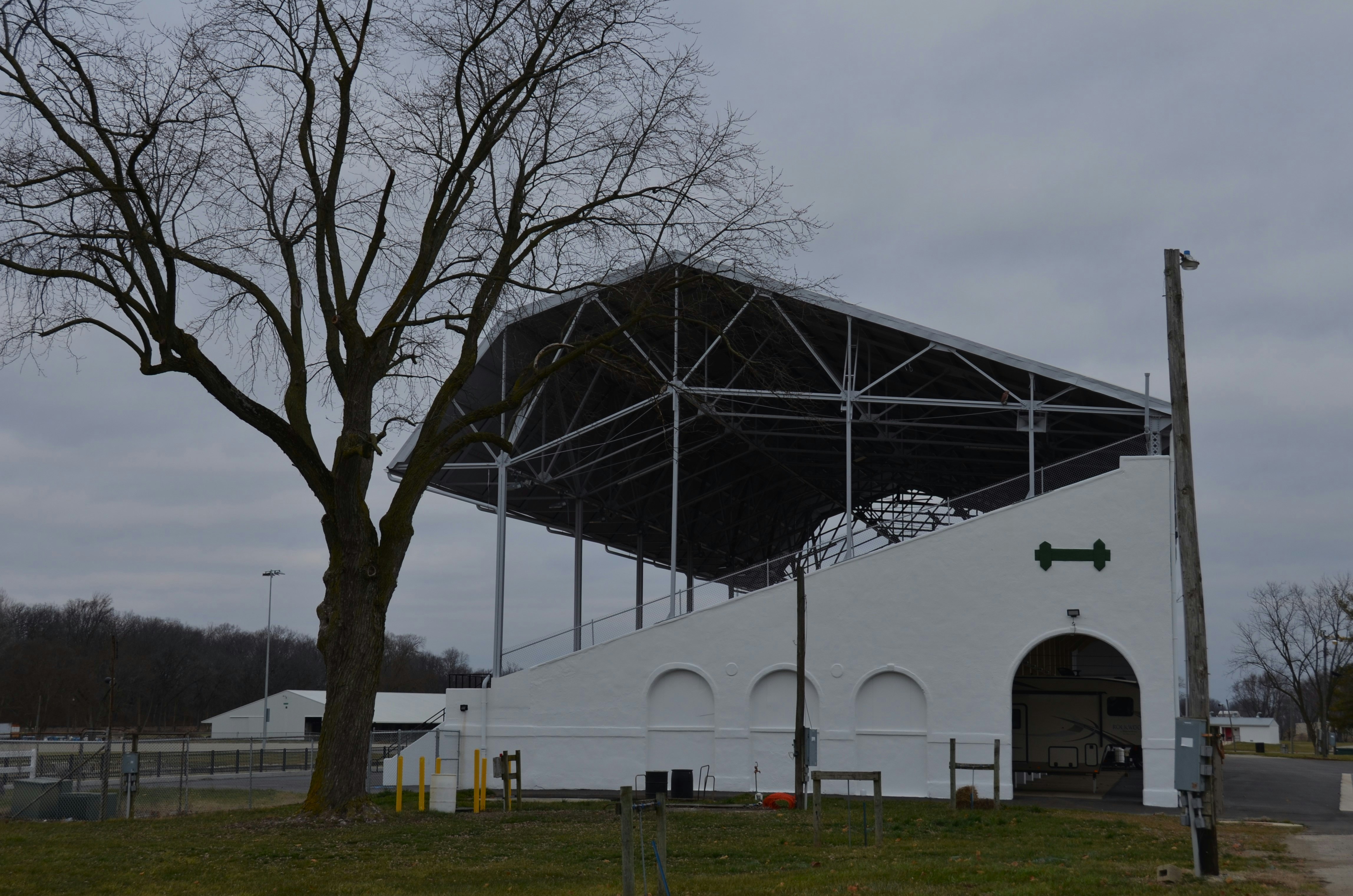 Arched White Field House Under an Overcast Sky, Framed by a Silent Tree