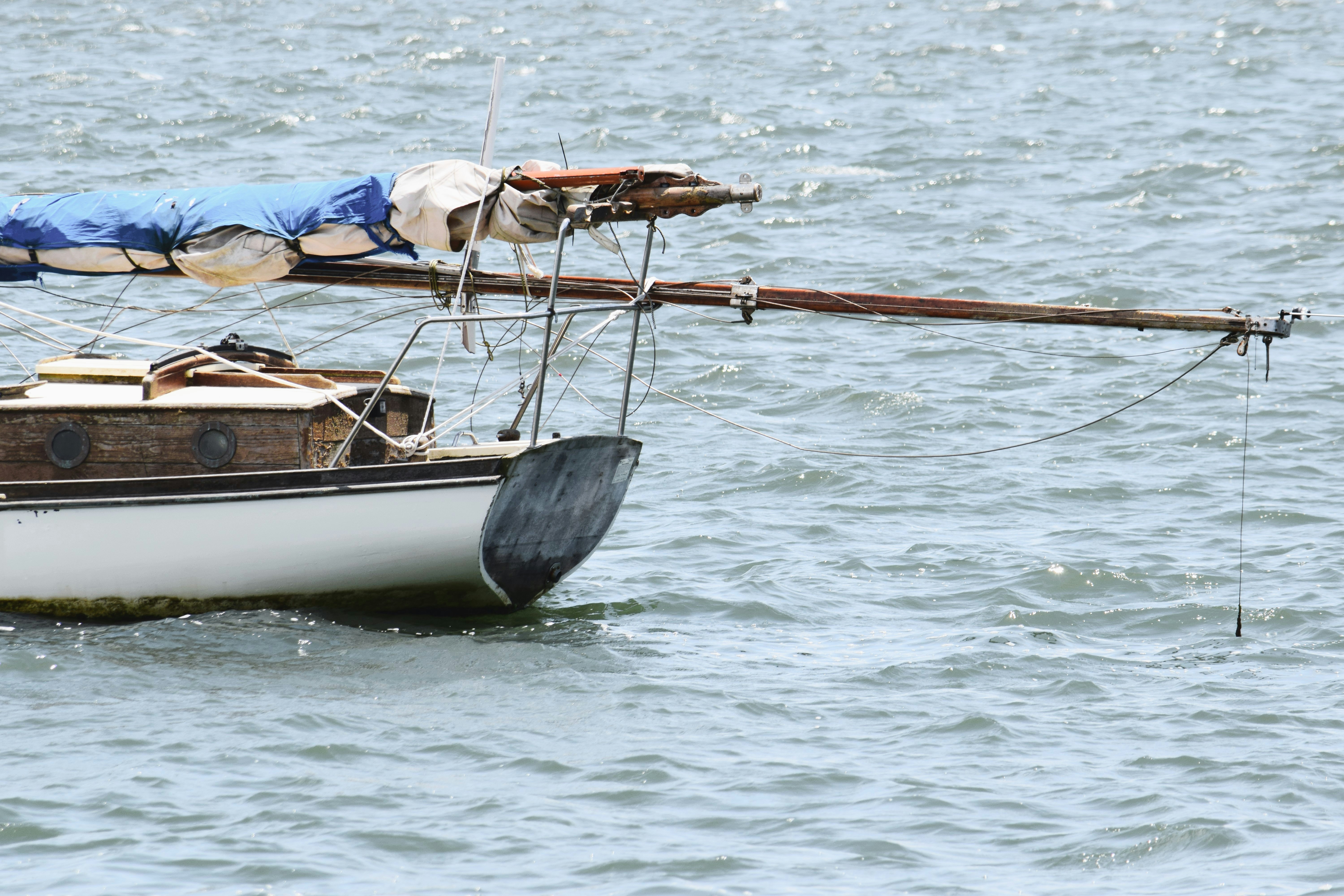 A sailboat with a blue tarp on it floating in the water photo – Free ...
