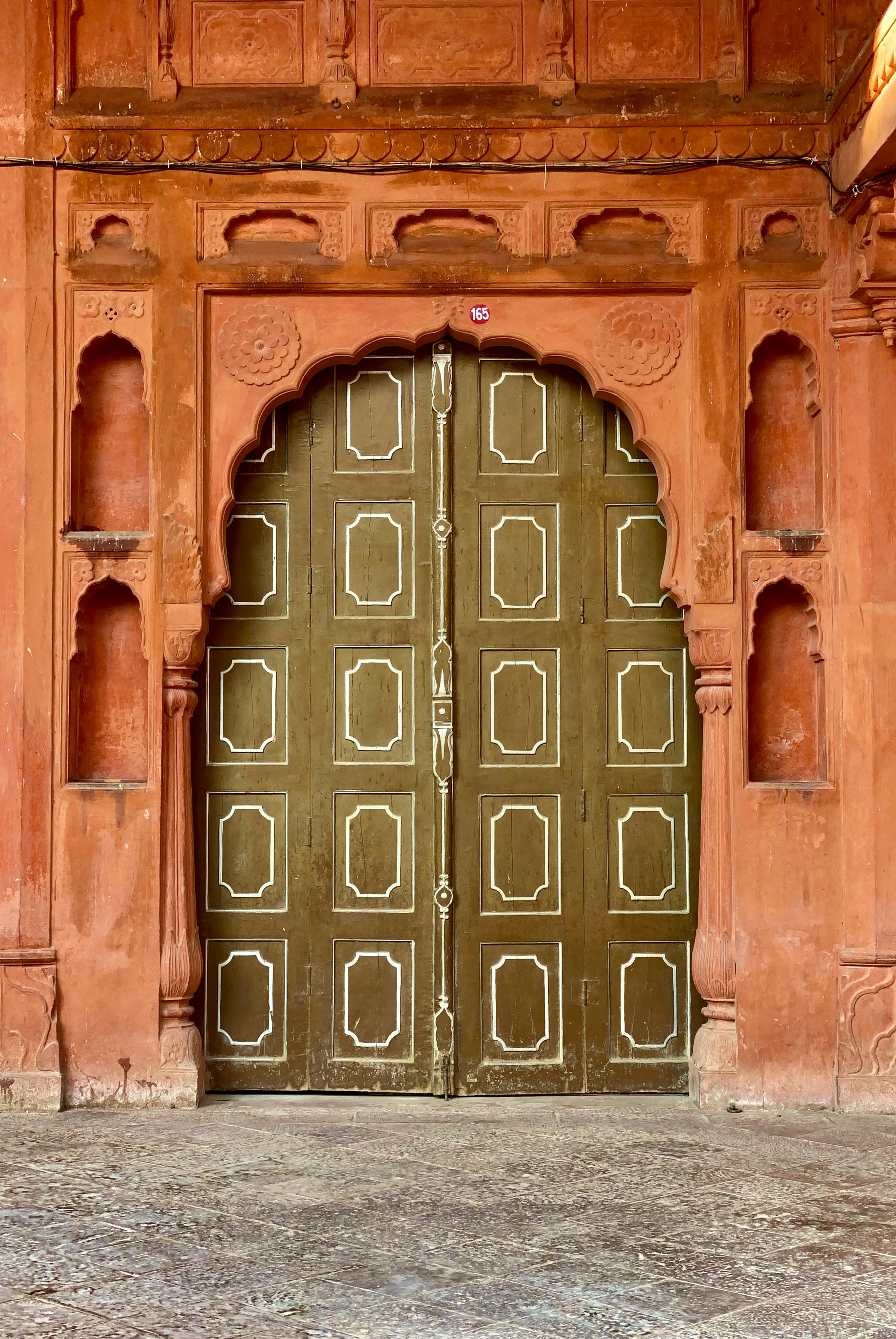 Archway of Carved Coral: An Olive-Green Door with White-Trim Panels