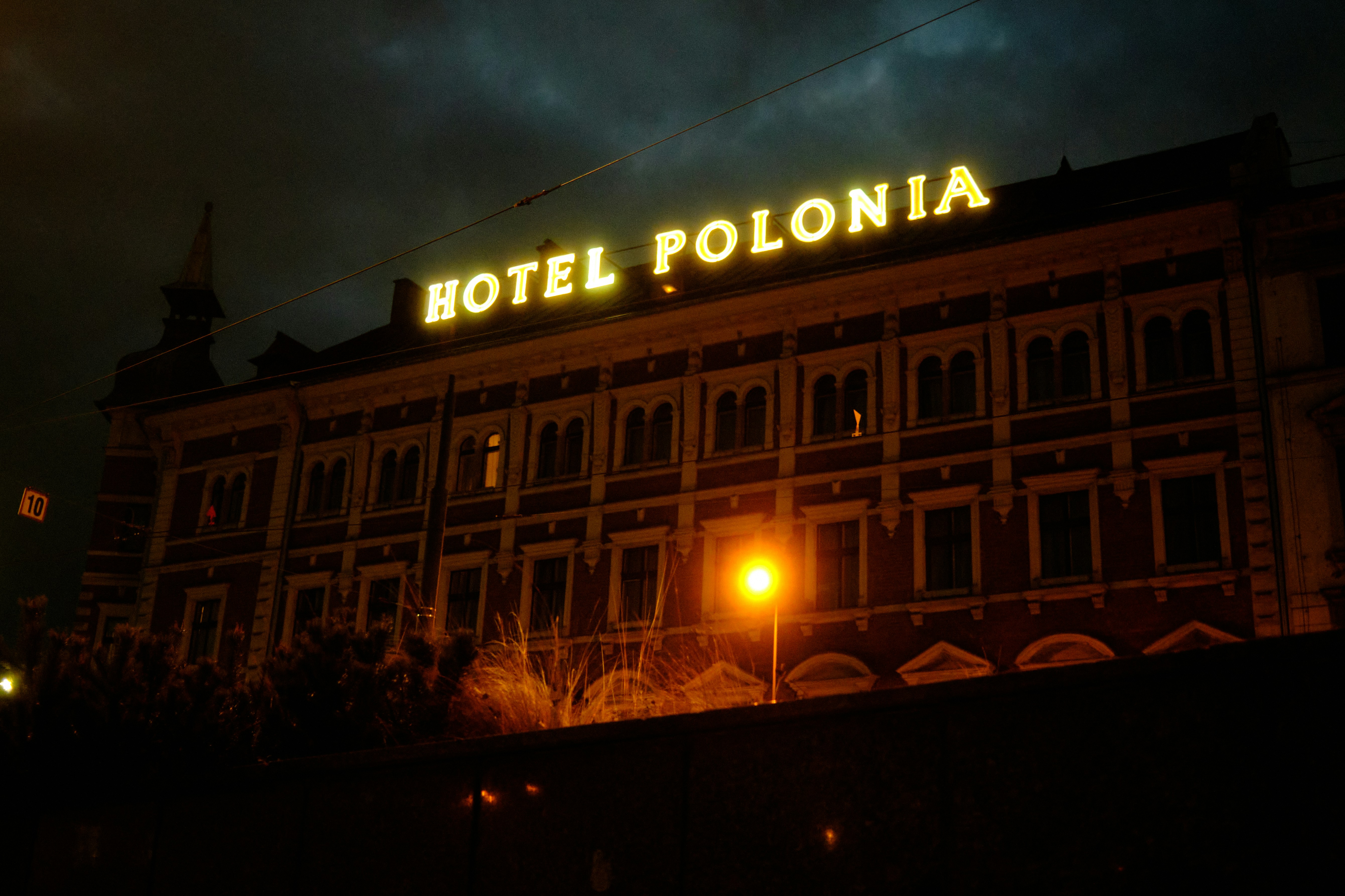 Neon Crown Over Polonia: Night Facade of a Historic Hotel