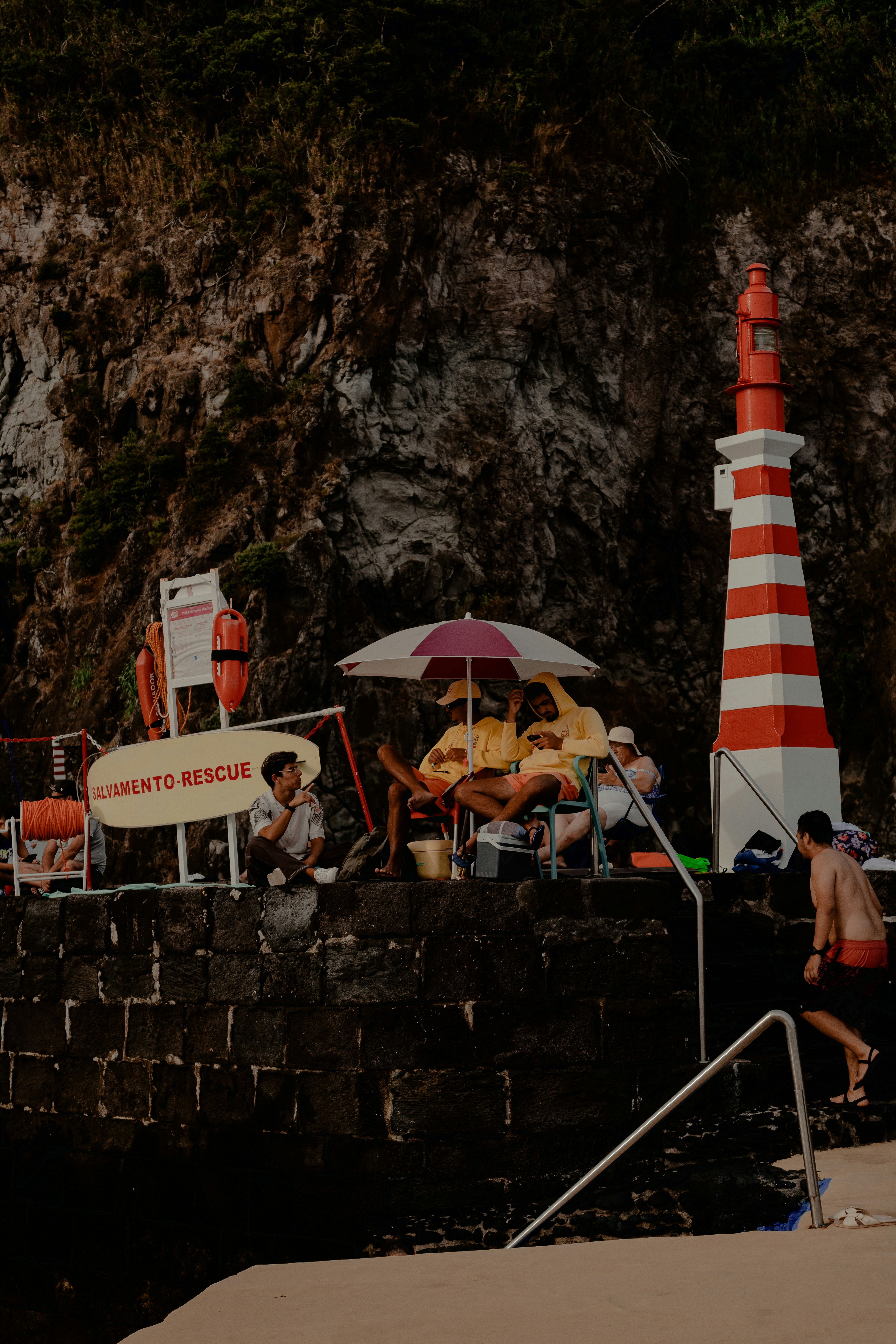 Umbrella Refuge by a Striped Lighthouse on a Quiet Shore