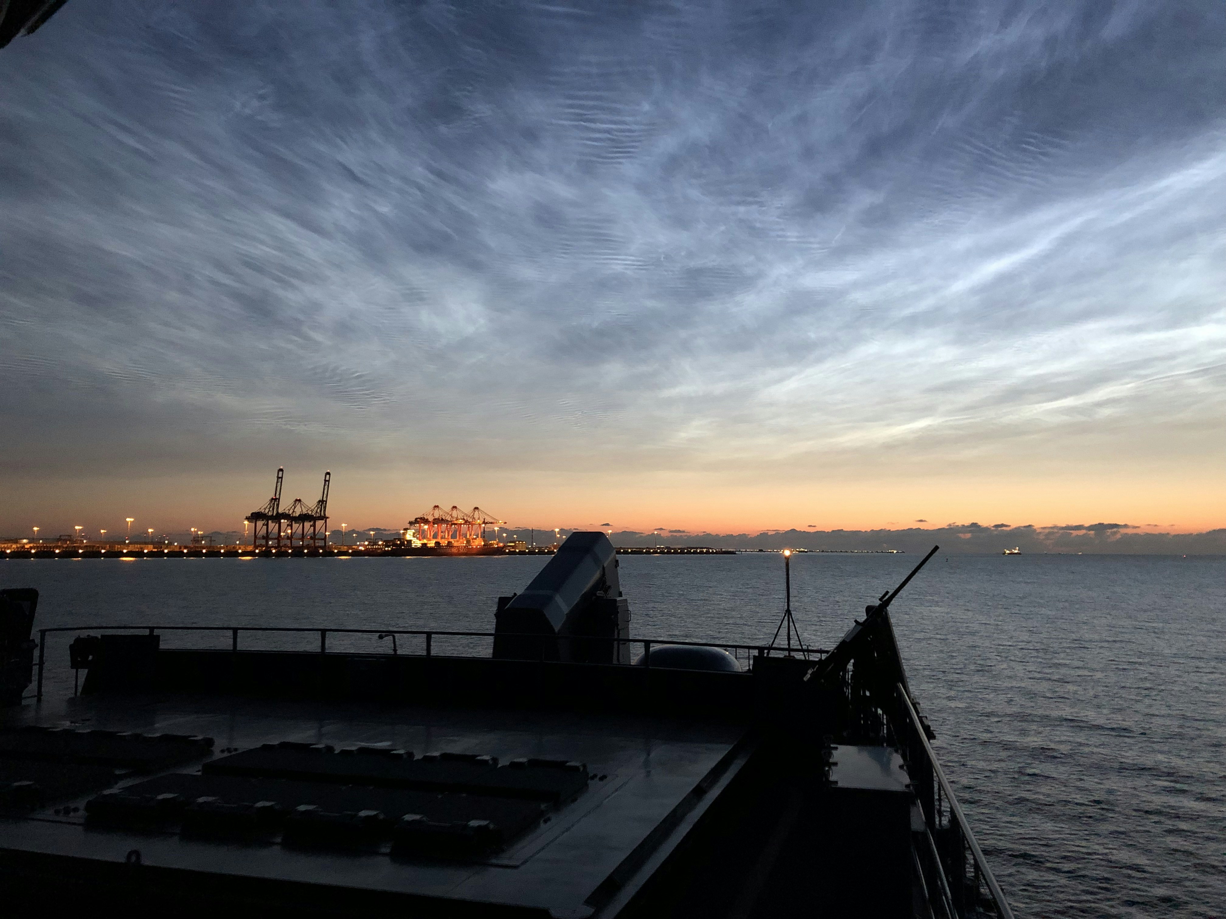 Dusk at the Dockyard: Cranes Framing a Quiet Harbor from the Bow