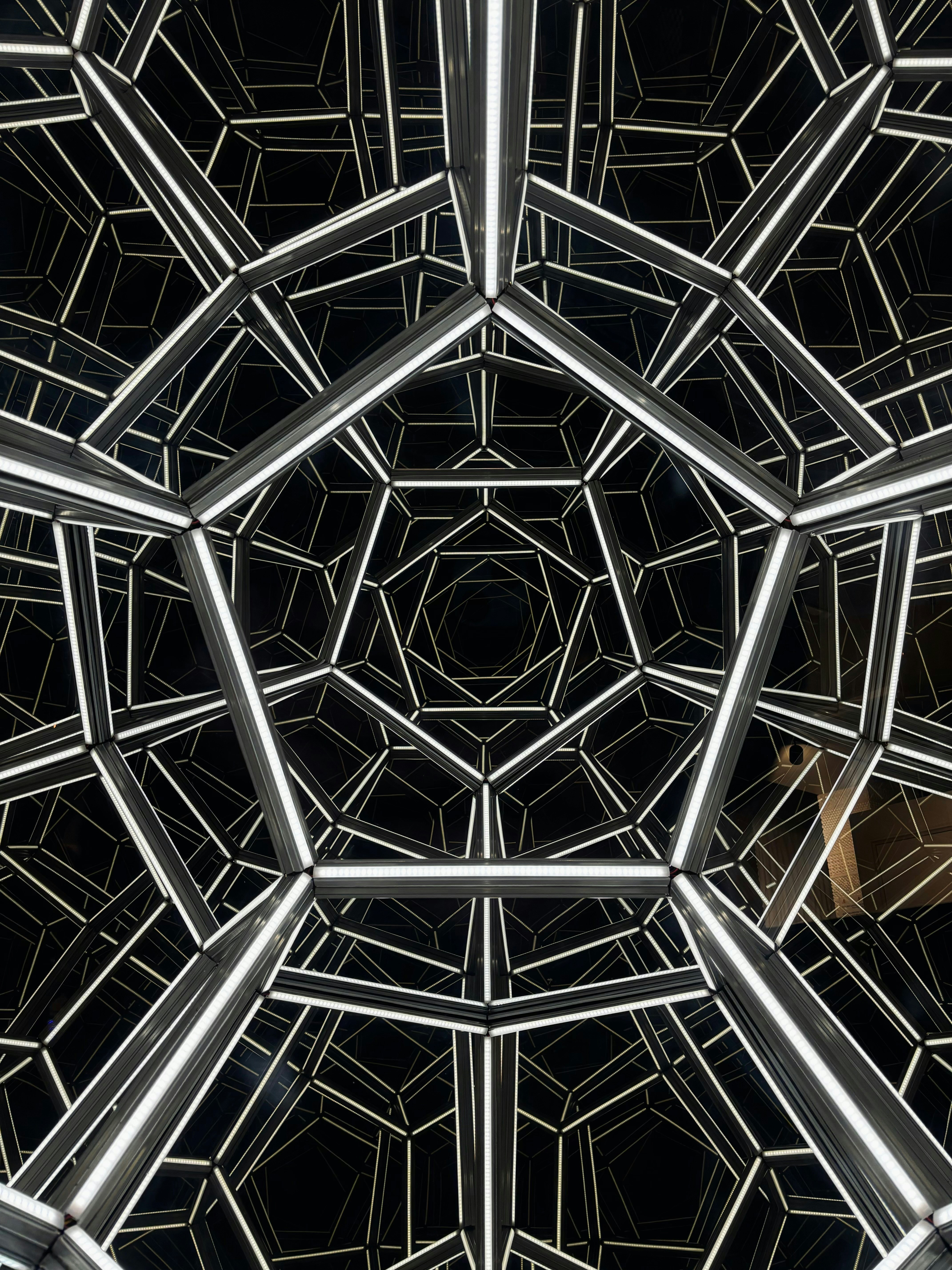 Black and white geometric ceiling with interlocking illuminated hexagonal patterns.