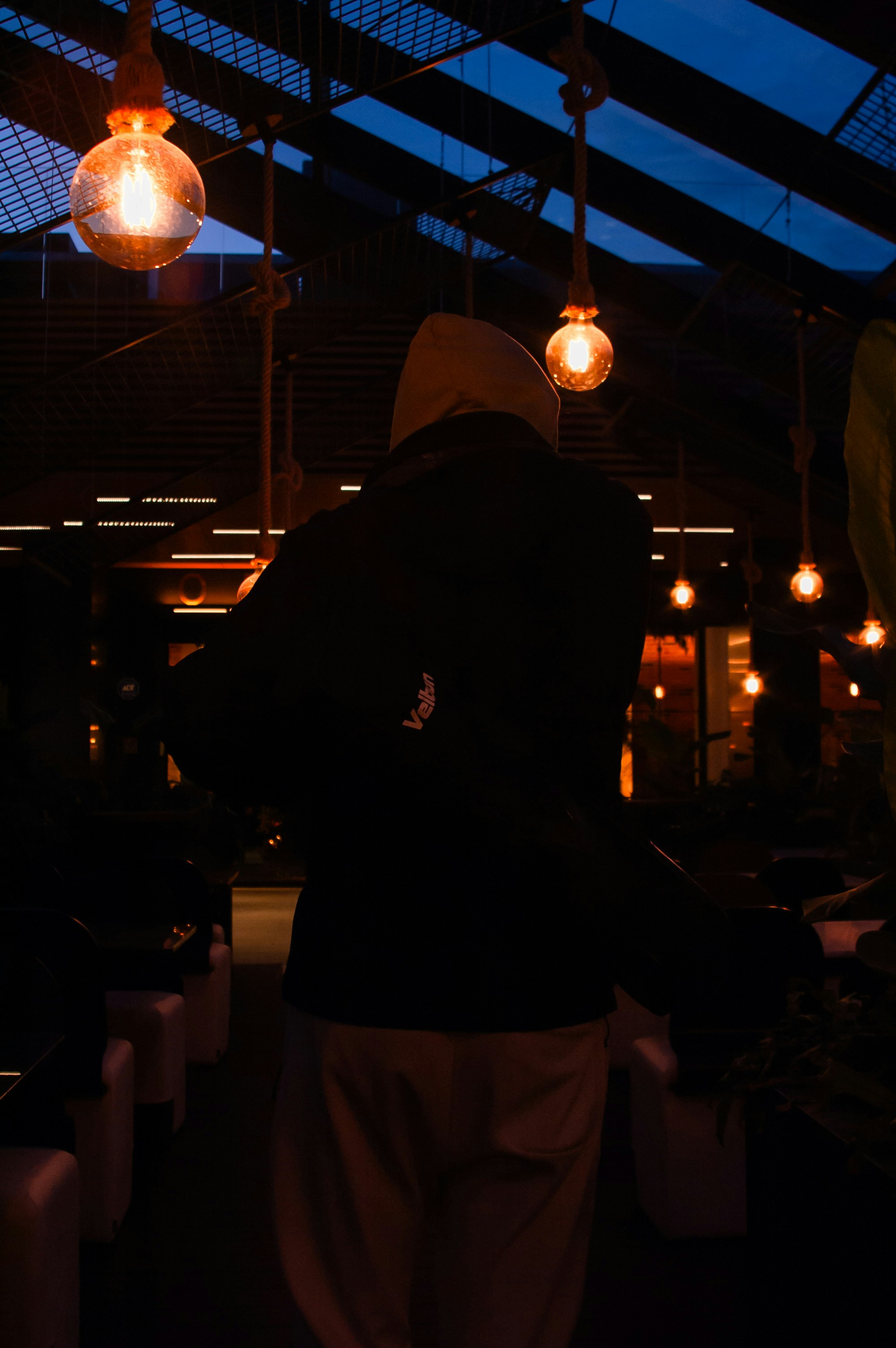 Amber Orbs and a Hooded Silhouette: Night Shift in an Industrial Lounge