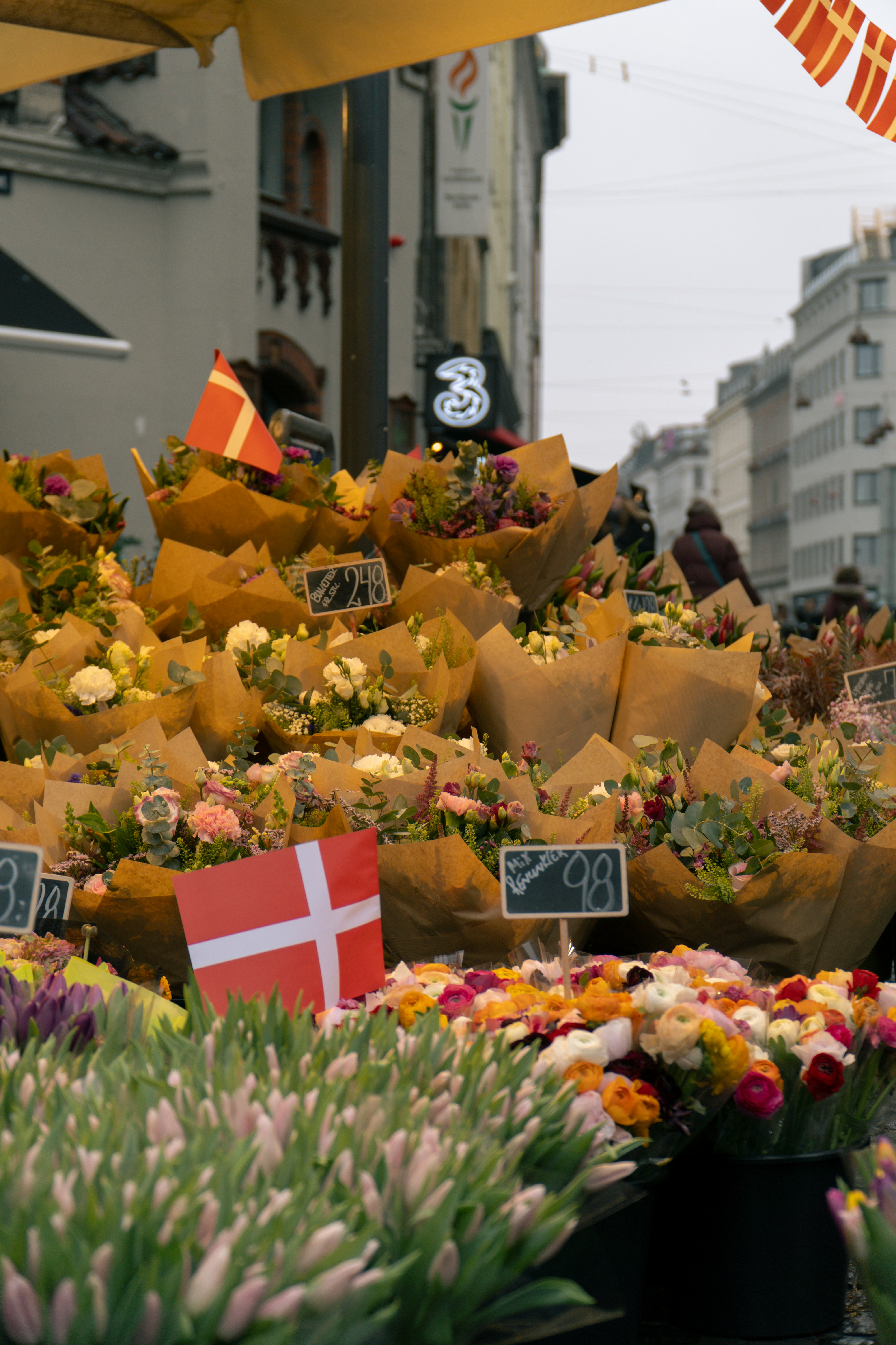Danish Flag Amid Wrapped Bouquets at a Lively Street Market