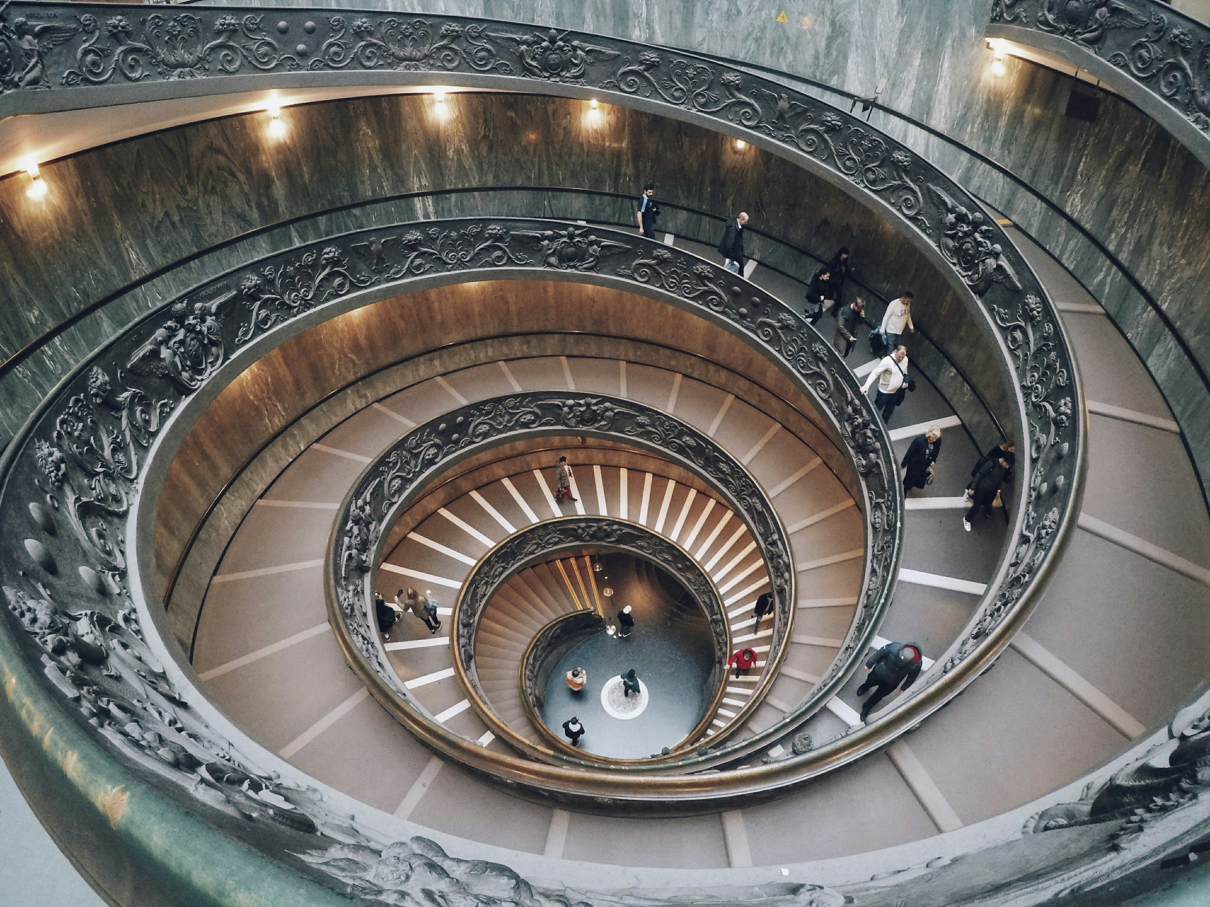 Concentric Descent: Aerial View of an Ornate Spiral Staircase Teeming with Visitors