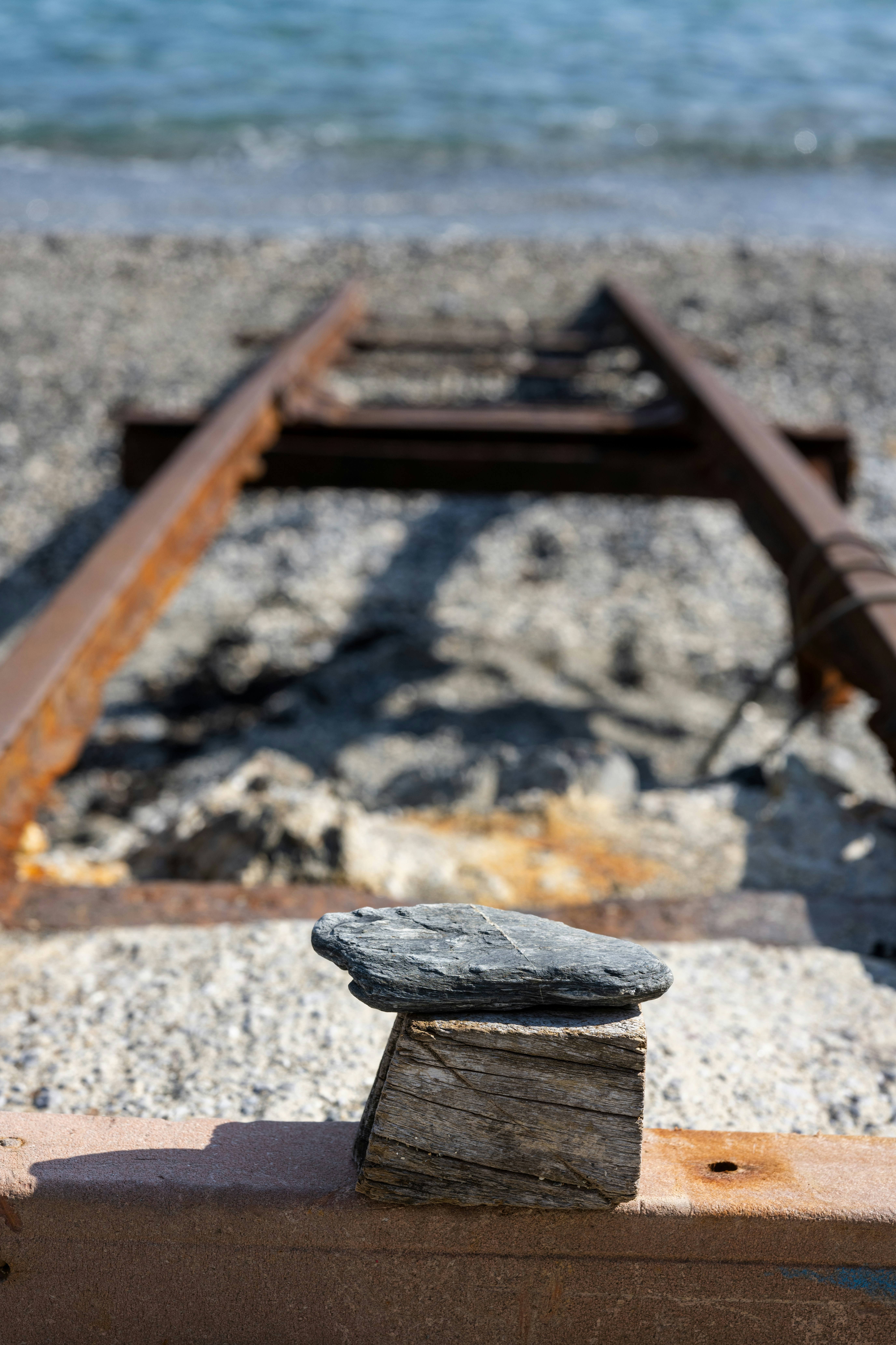Stone Stack on a Rusted Rail, Framing the Quiet Sea