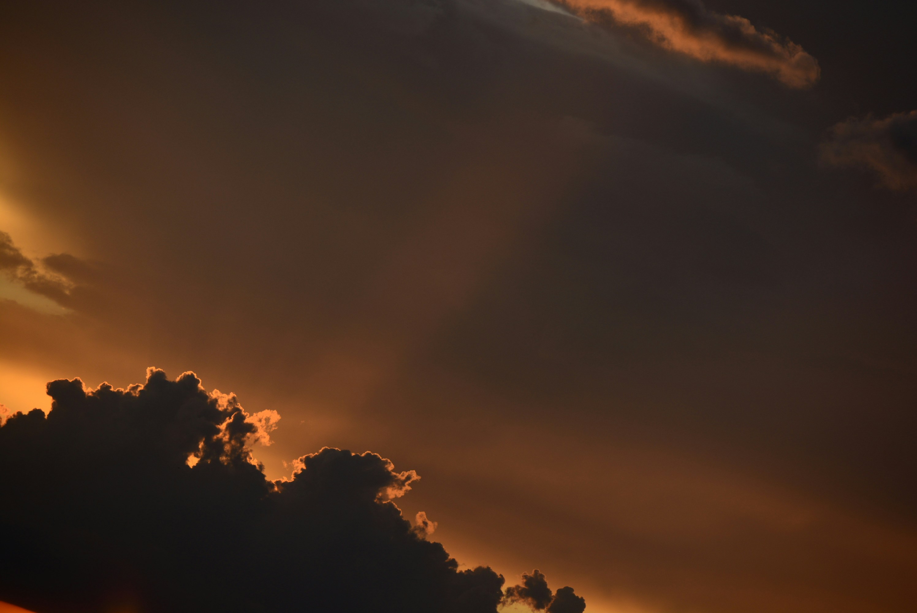 Dark clouds illuminated by the warm glow of a setting sun, creating a dramatic interplay of light and shadow.