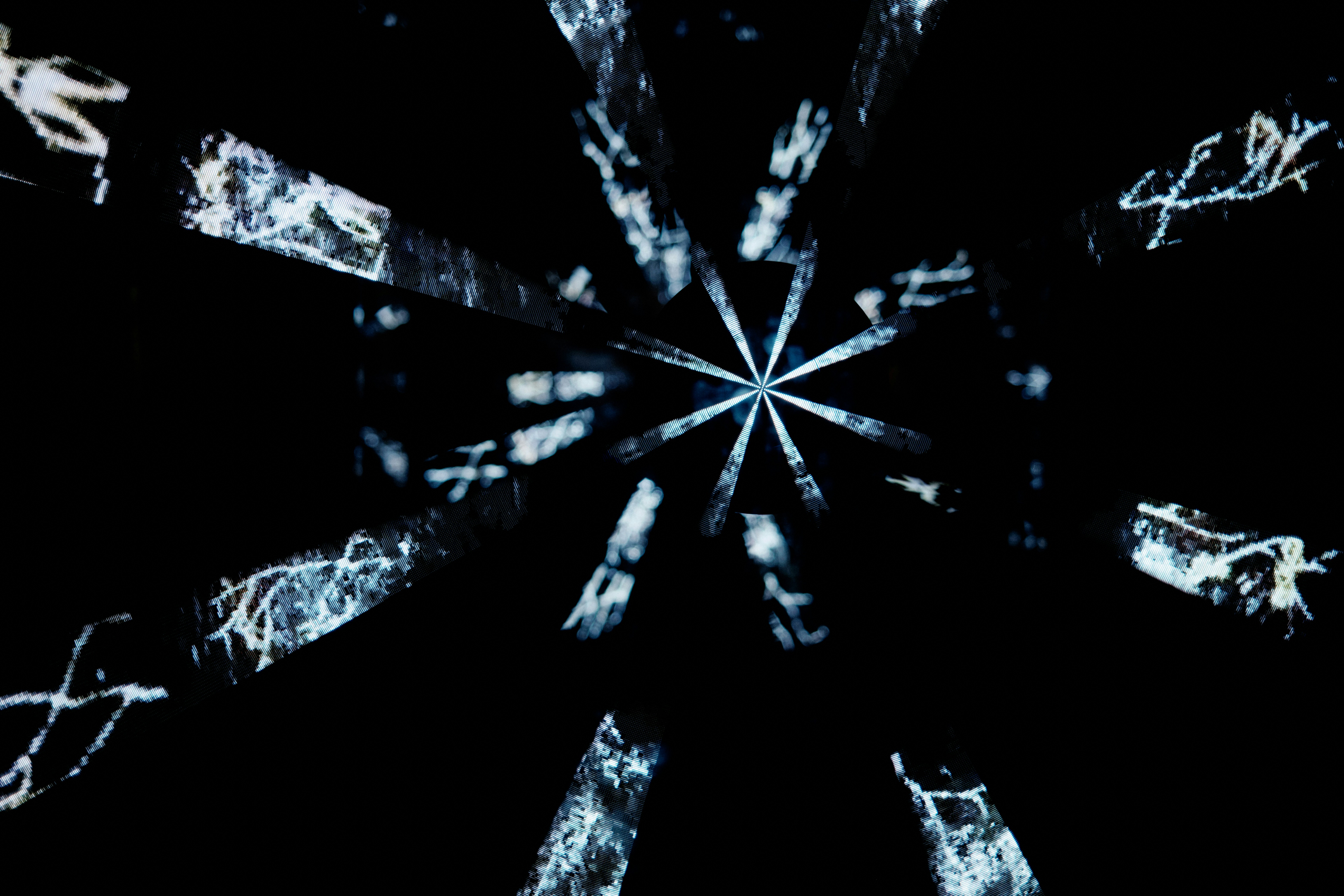 Abstract spiral formation created by reflective surfaces in a dark environment, emphasizing contrast and depth.