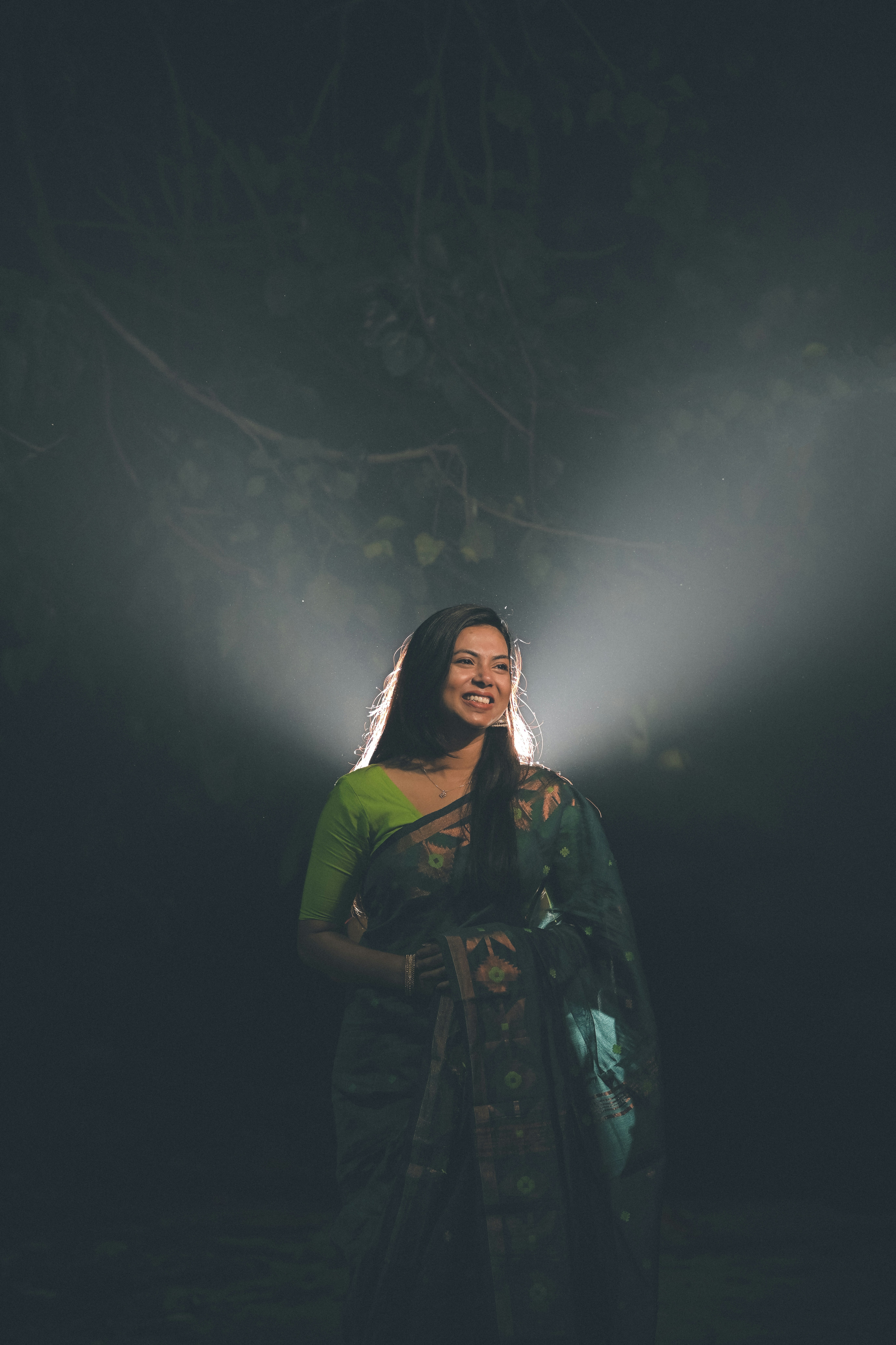 a woman standing in the dark with a light shining on her
