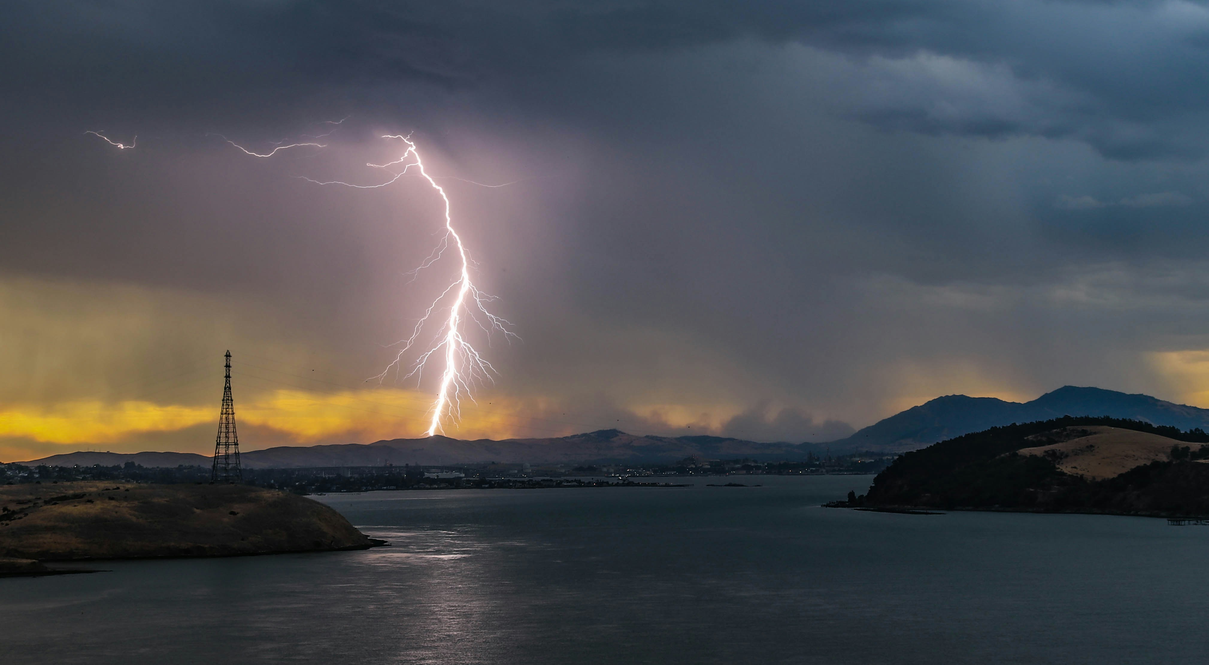 A lightning bolt is seen over a body of water photo – Free Benicia ...