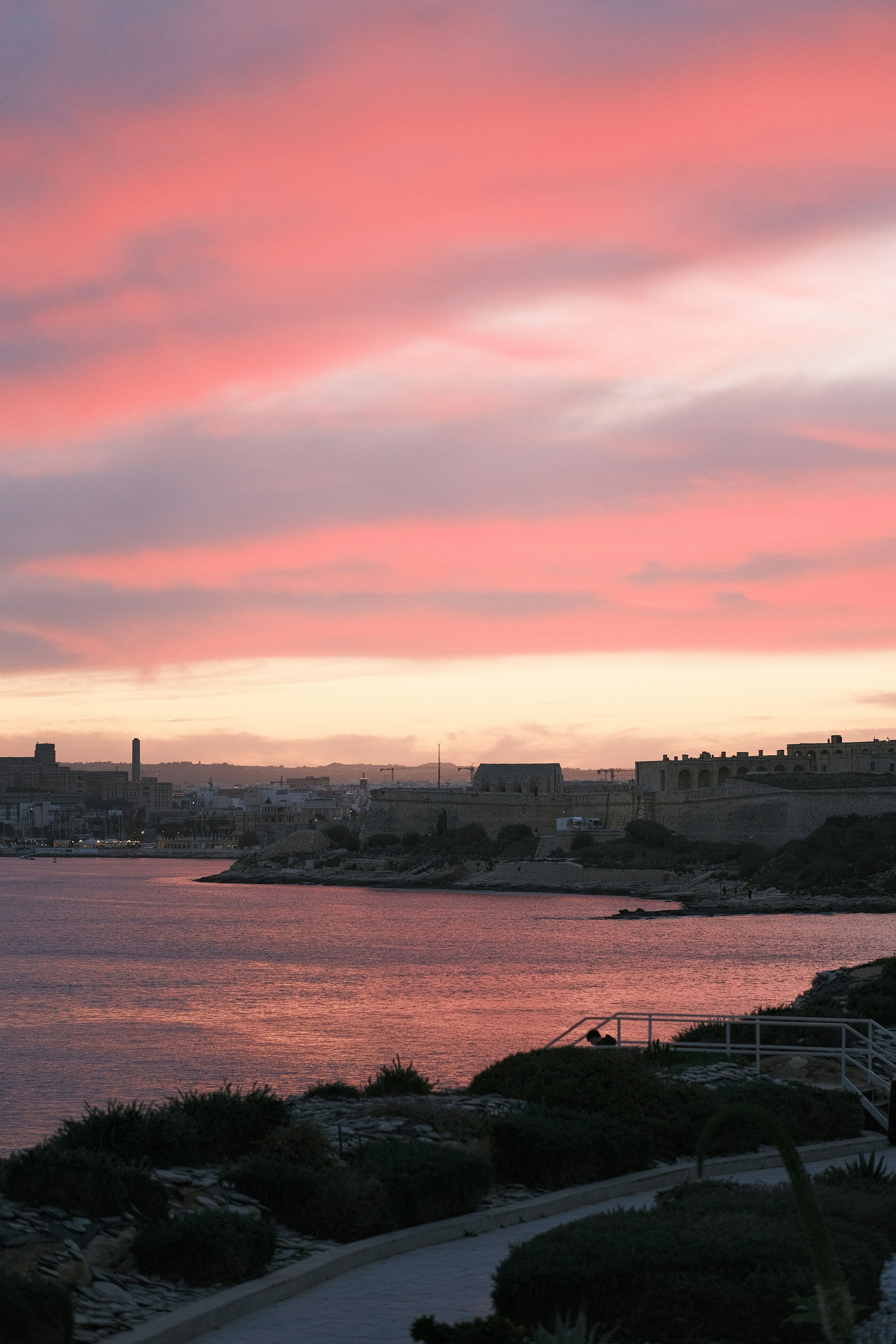 Coral Sky Over a Quiet Harbor Promenade at Dusk
