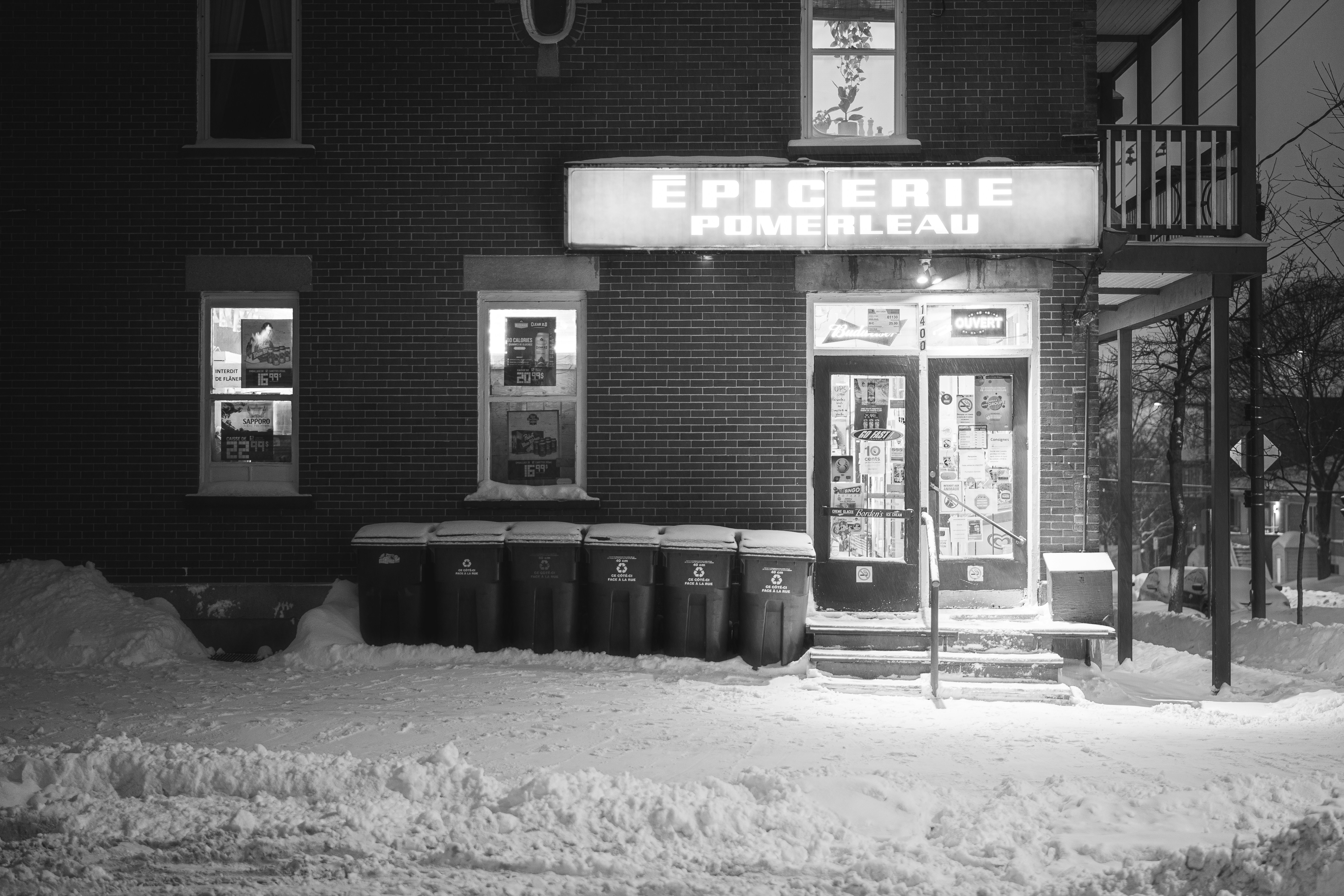 Snowy Epicerie Doorway: Quiet Night Glow on Brick Facade