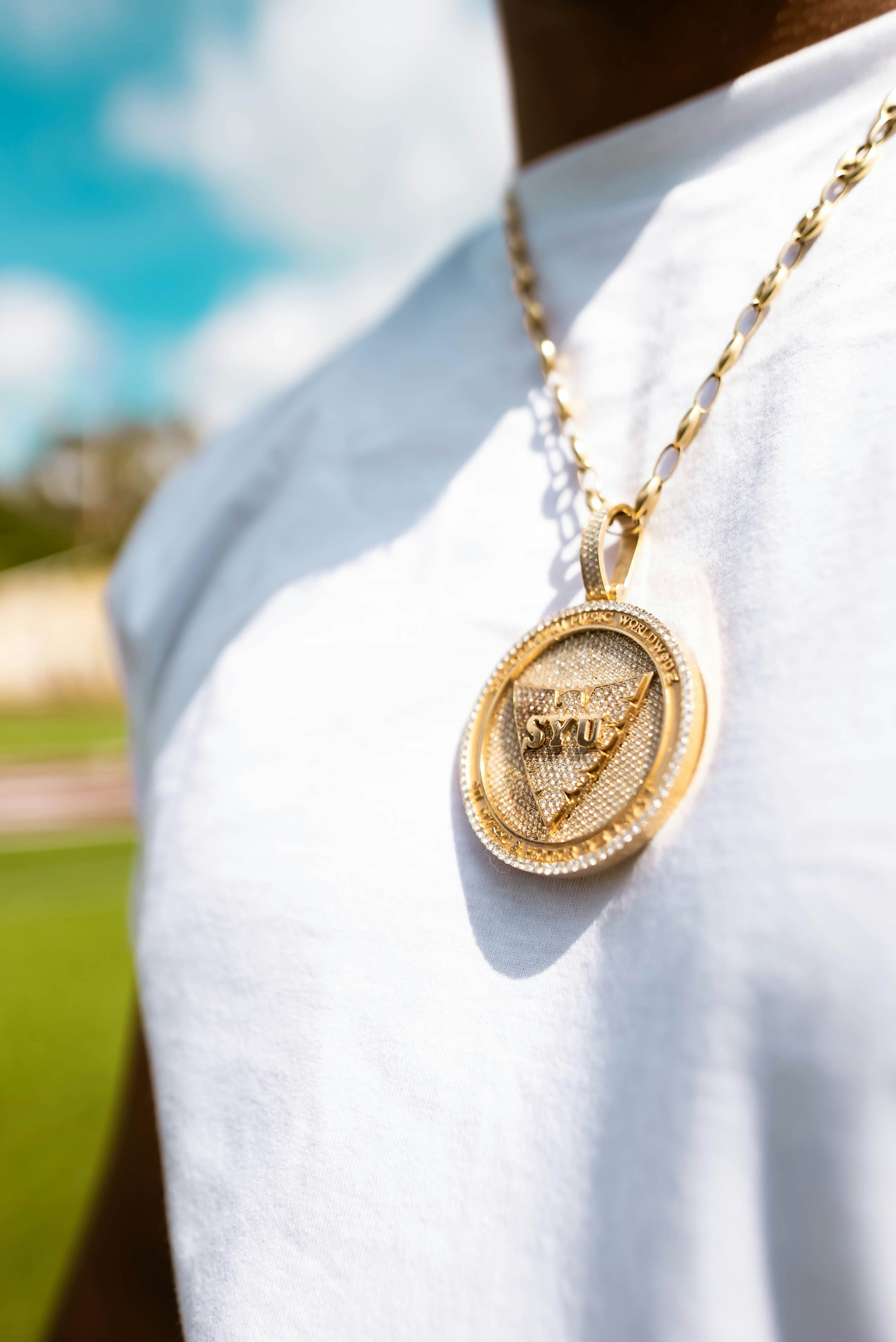 Gold Pendant Gleam: A Close-Up of Shine Against White Cotton