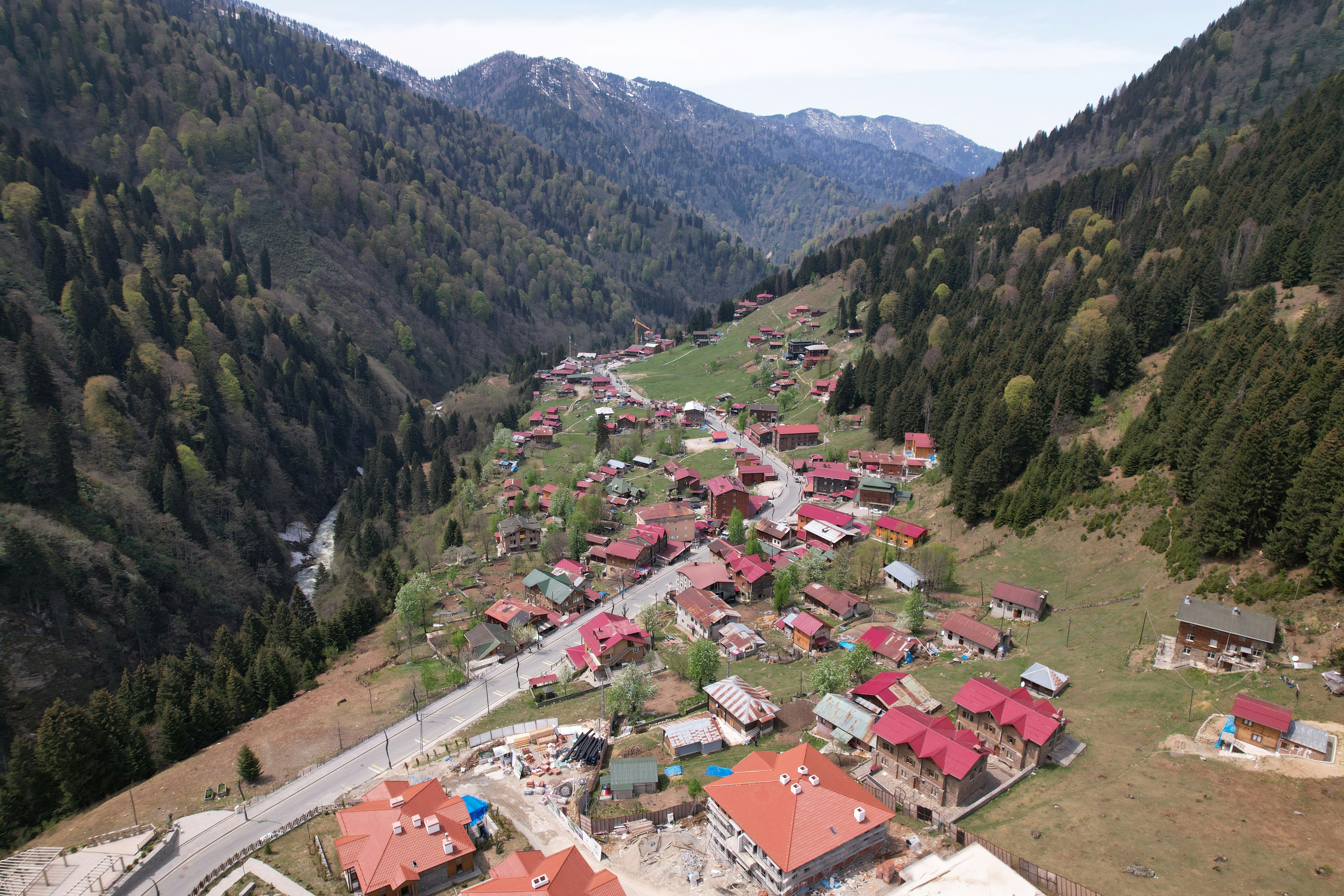 Aerial view of a mountain village with red-roofed houses nestled in a lush valley.